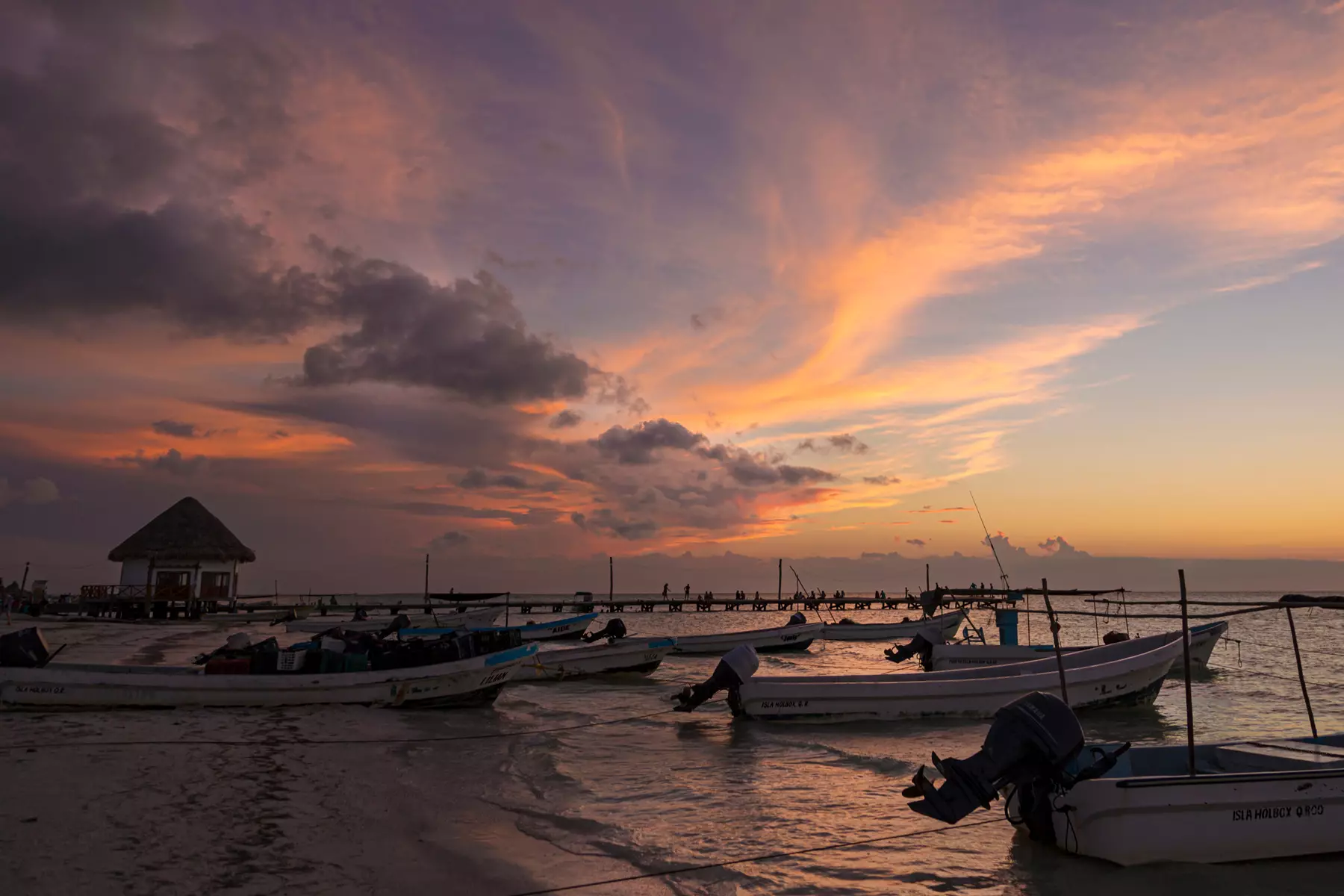 Boatoj marborde ĉe sunsubiro en Holbox, Meksiko