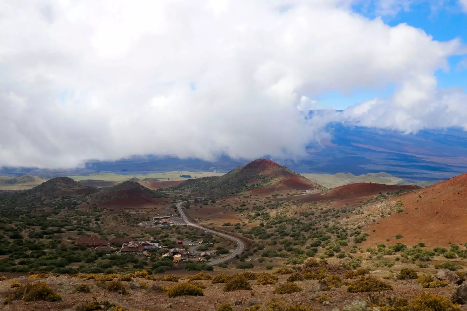 Maaliline Mauna Kea maastik sillutatud teega vanade kraatrite vahel ja vaade Mauna Loale pilvedes.