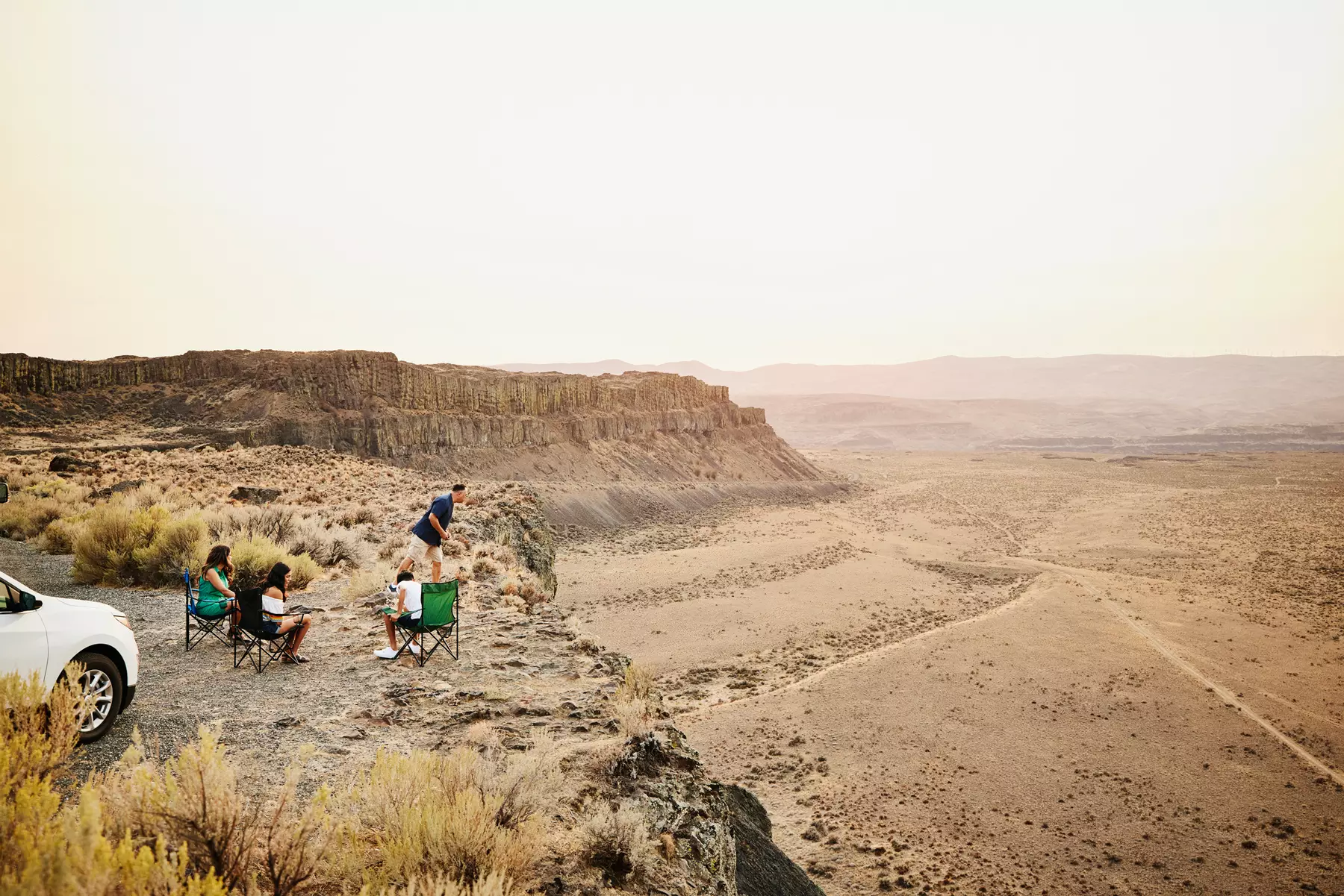 משפחה מתרווחת בכיסאות מחנה ליד קניון המדבר במהלך טיול כביש הקיץ