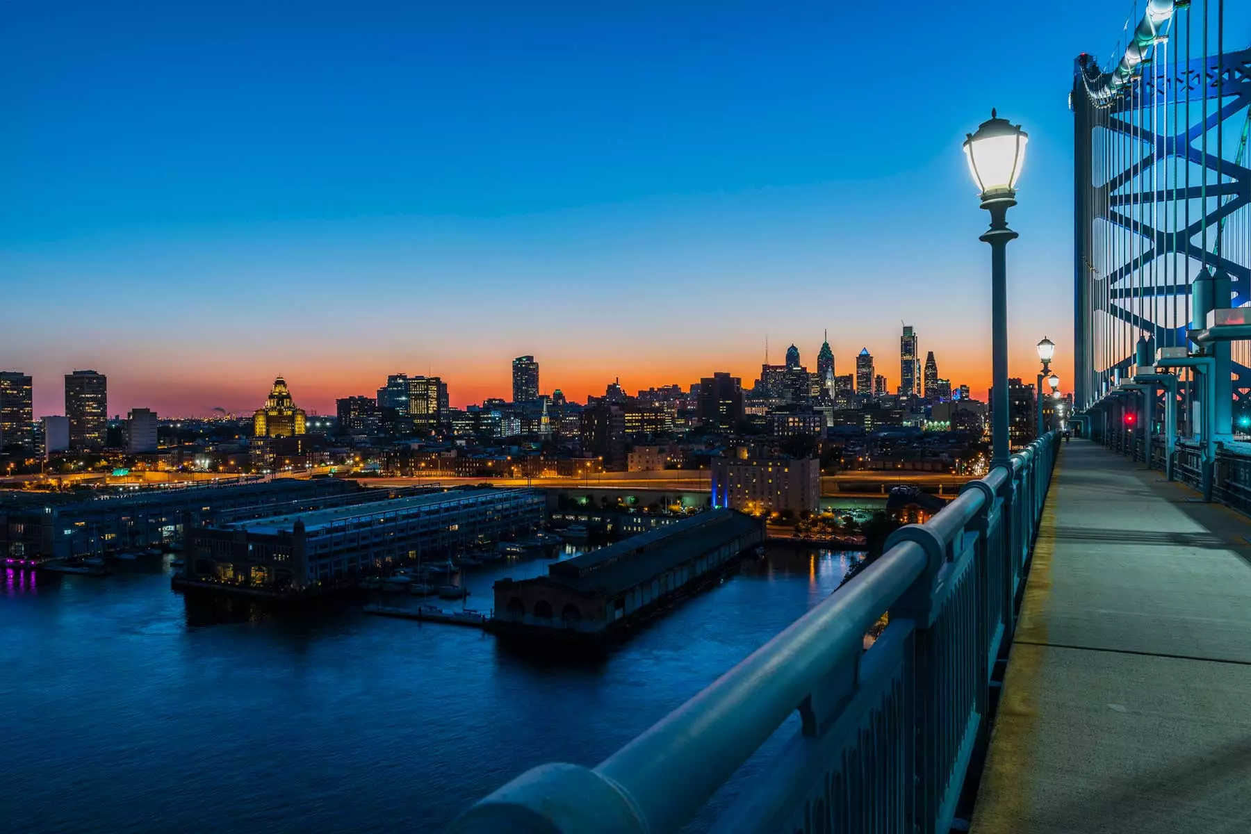 Philadelpia Downtown ao pôr do sol. A vista da ponte Benjamin Franklin sobre os cais na cidade velha e no rio Delaware.