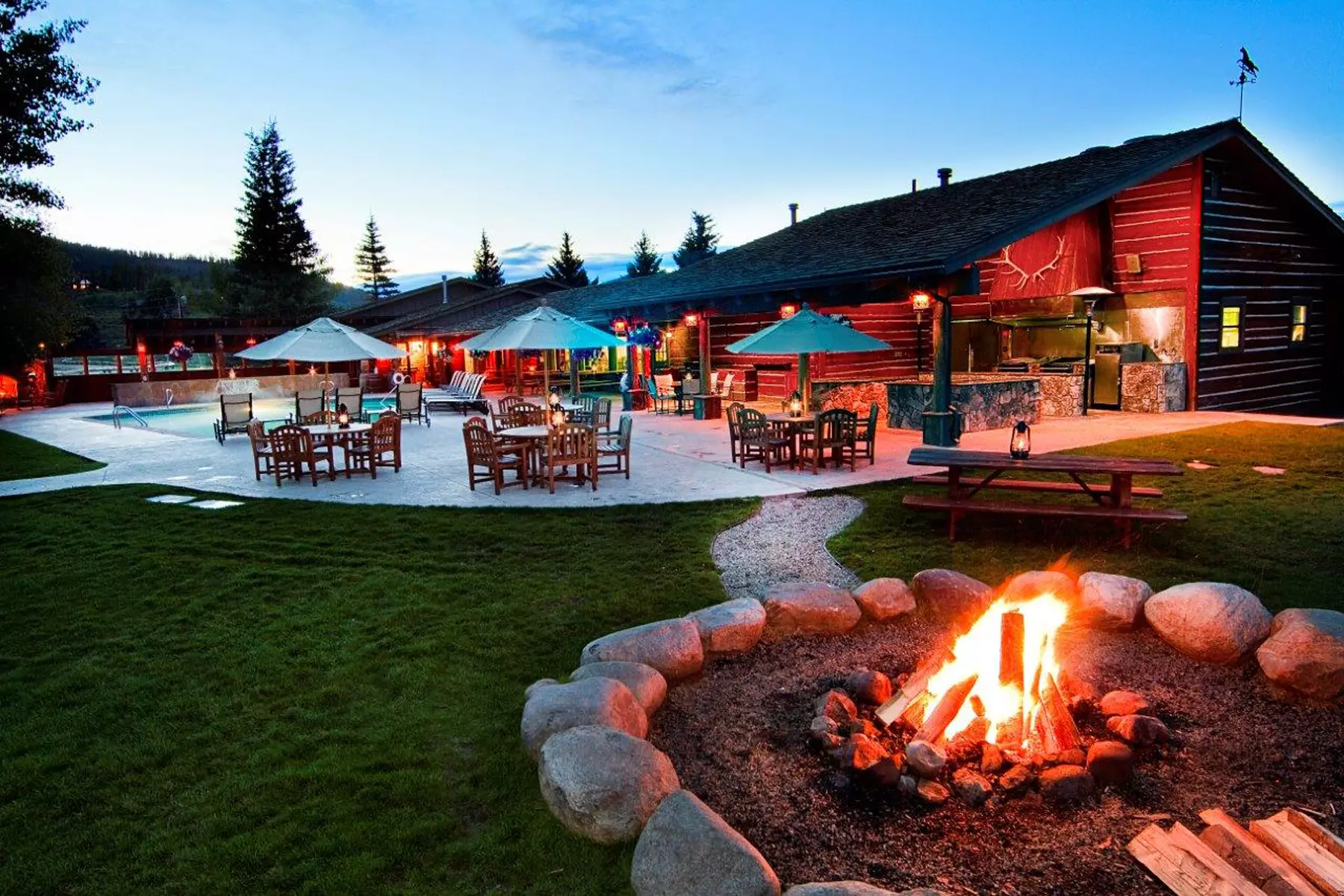 Außenansicht der C Lazy U Ranch in der Abenddämmerung mit der Feuerstelle im Sommer