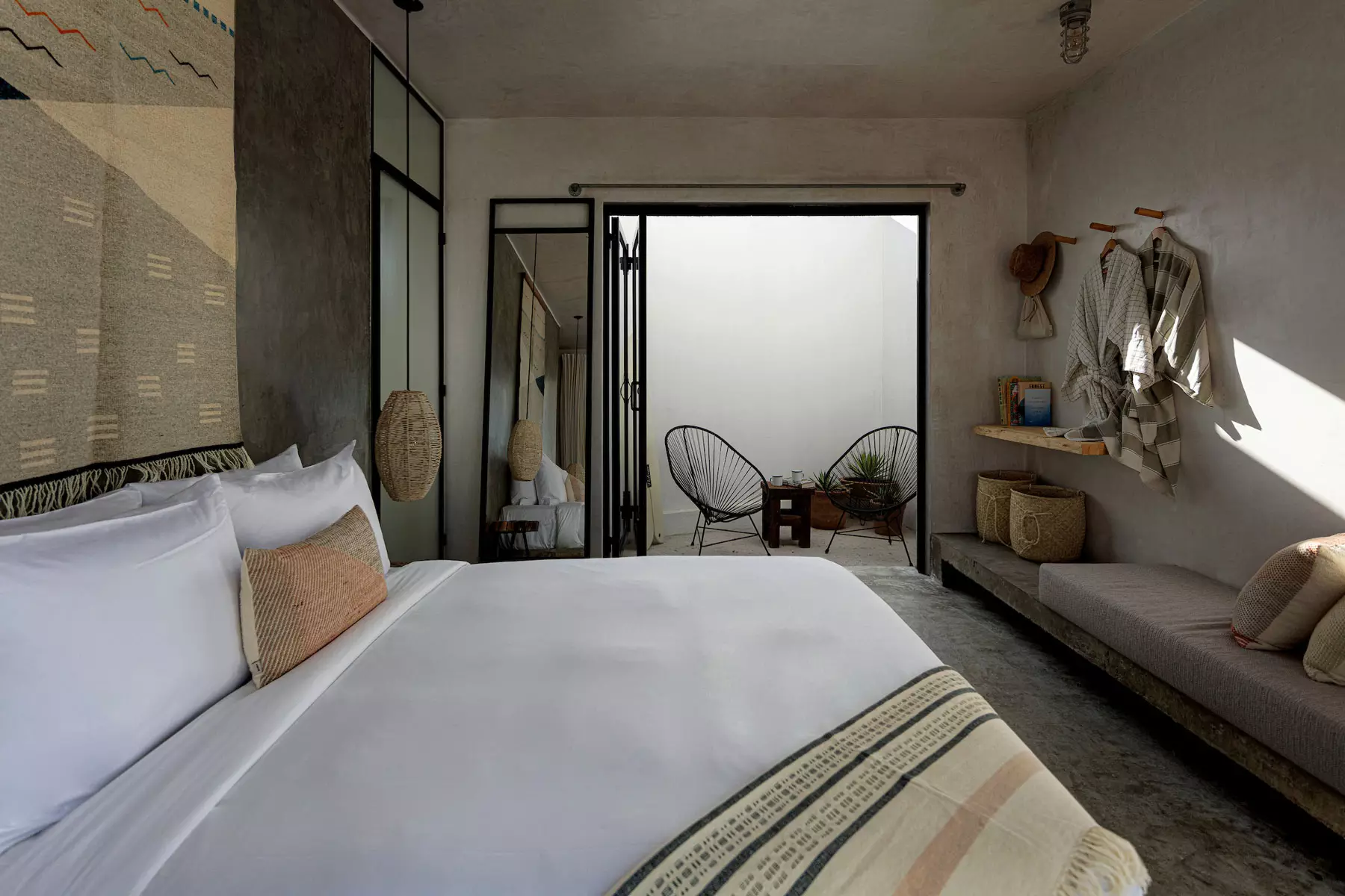 Drift Hotel w sypialni San Jose del Cabo szczegółowo o minimalistycznym designie i naturalnych teksturach, takich jak drewno, plecione kosze i beton