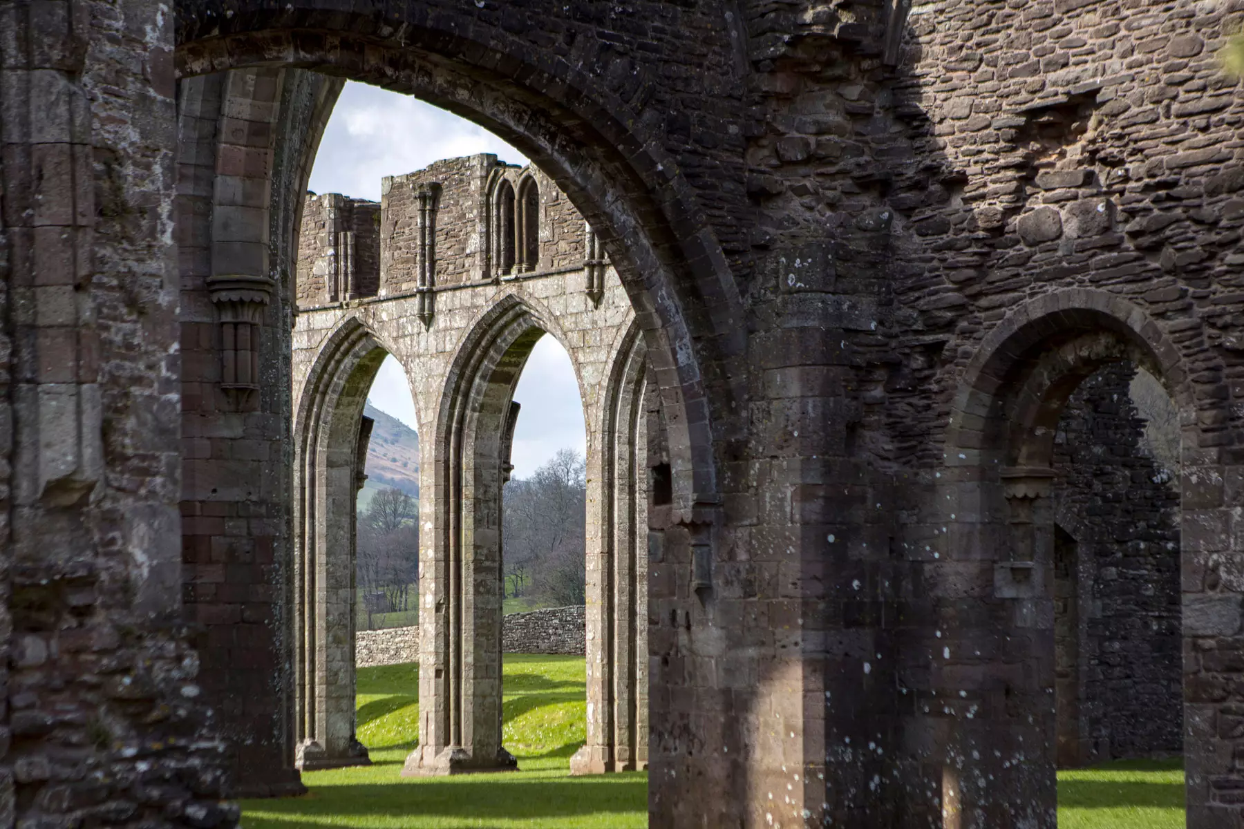 Fileira de arcos de pedra antigos arruinados em Llanthony Priory, Black Mountains, Monmouthshire, País de Gales, Reino Unido.