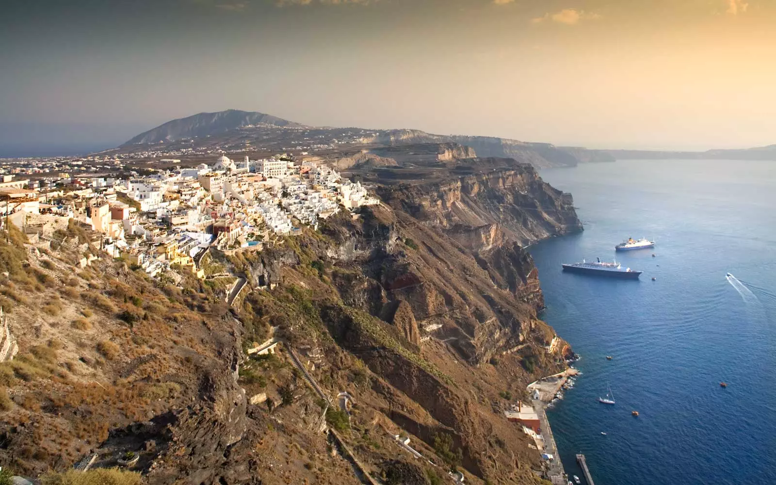 Vista ao atardecer ao longo da caldeira colapsada da aldea de Fira mostrando a típica arquitectura grega encaramada ao lado do bordo do cráter de Santorini, Fira, Santorini, Cícladas, Grecia