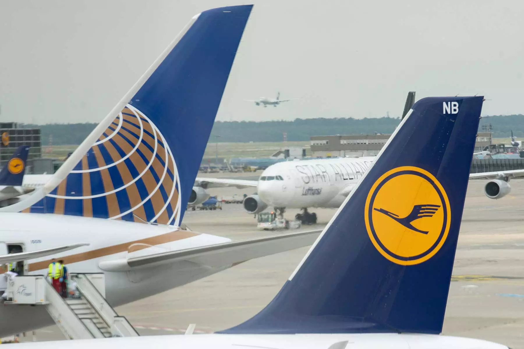 Sebuah pesawat penumpang Lufthansa (kanan) dan United Airlines berdiri di apron bandara.