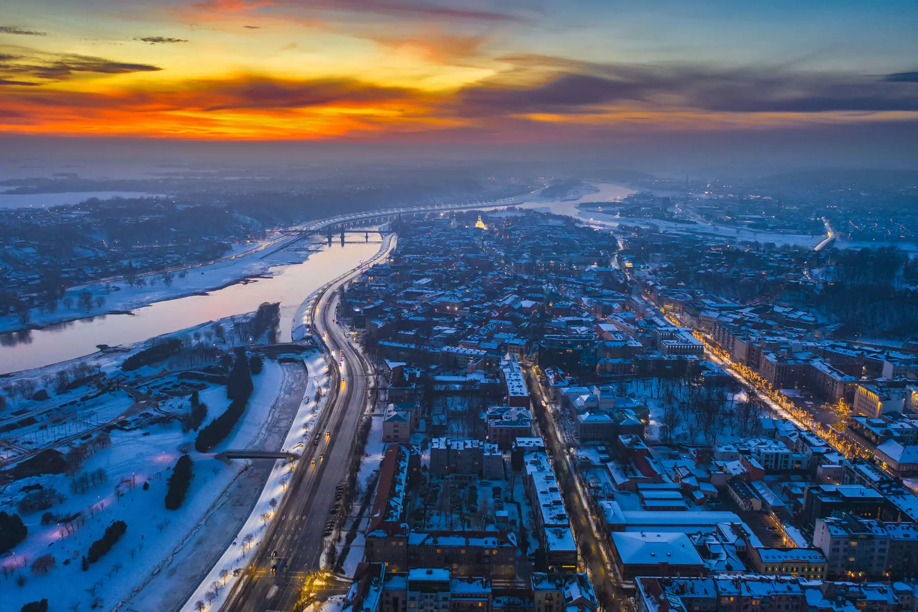 Naplemente Kaunasban, Litvániában télen, hó borítja a tájat