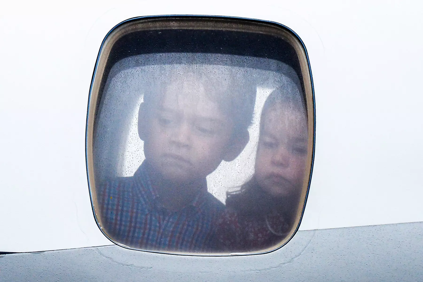 La princesa Charlotte de Cambridge y el príncipe George de Cambridge miran por la ventana del avión cuando llegan al aeropuerto de Varsovia durante una visita oficial a Polonia y Alemania el 17 de julio de 2017 en Varsovia, Polonia.