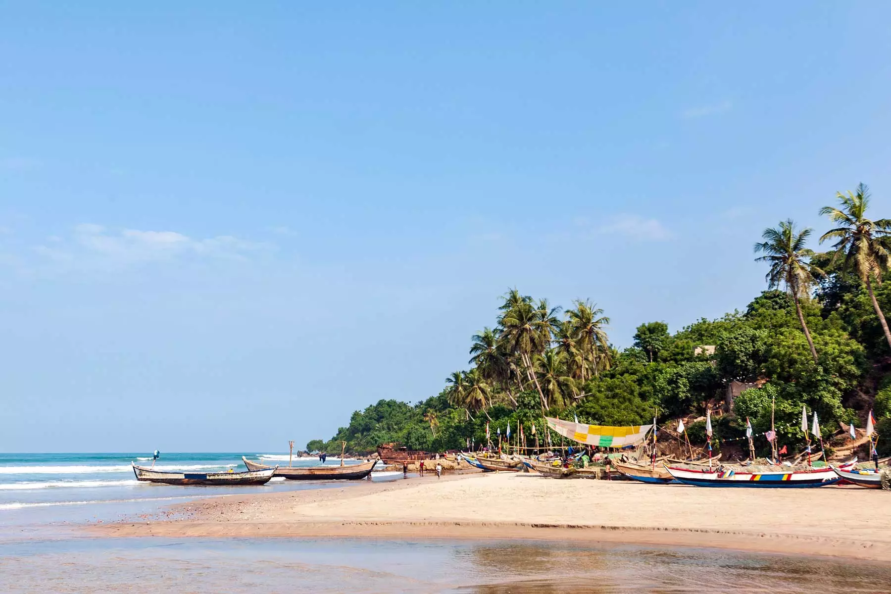 Plážová vesnice s dřevěnými rybářskými čluny na Atlantském oceánu v Accra, Ghana