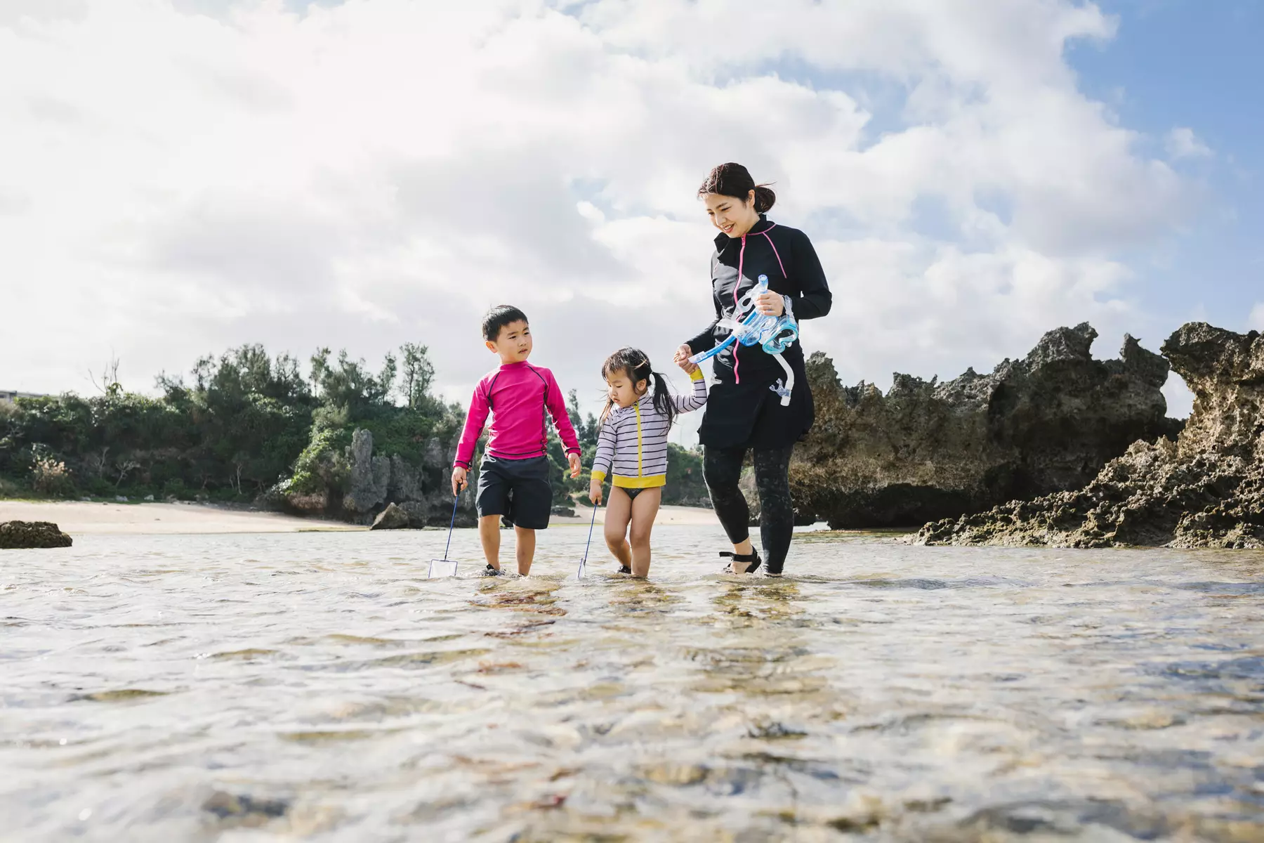 Madre asiatica, figlio e figlia che giocano in spiaggia nell'isola di Okinawa.