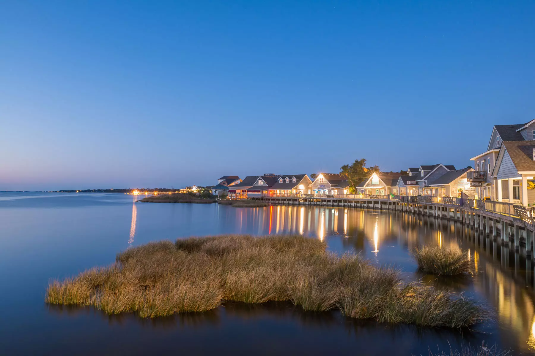 IWaterfront Iivenkile eDada ngorhatya kukhanyiswe izibane ezivenkileni. Ukubonakaliswa kwezibane emanzini kunye nesibhakabhaka esiluhlaza.