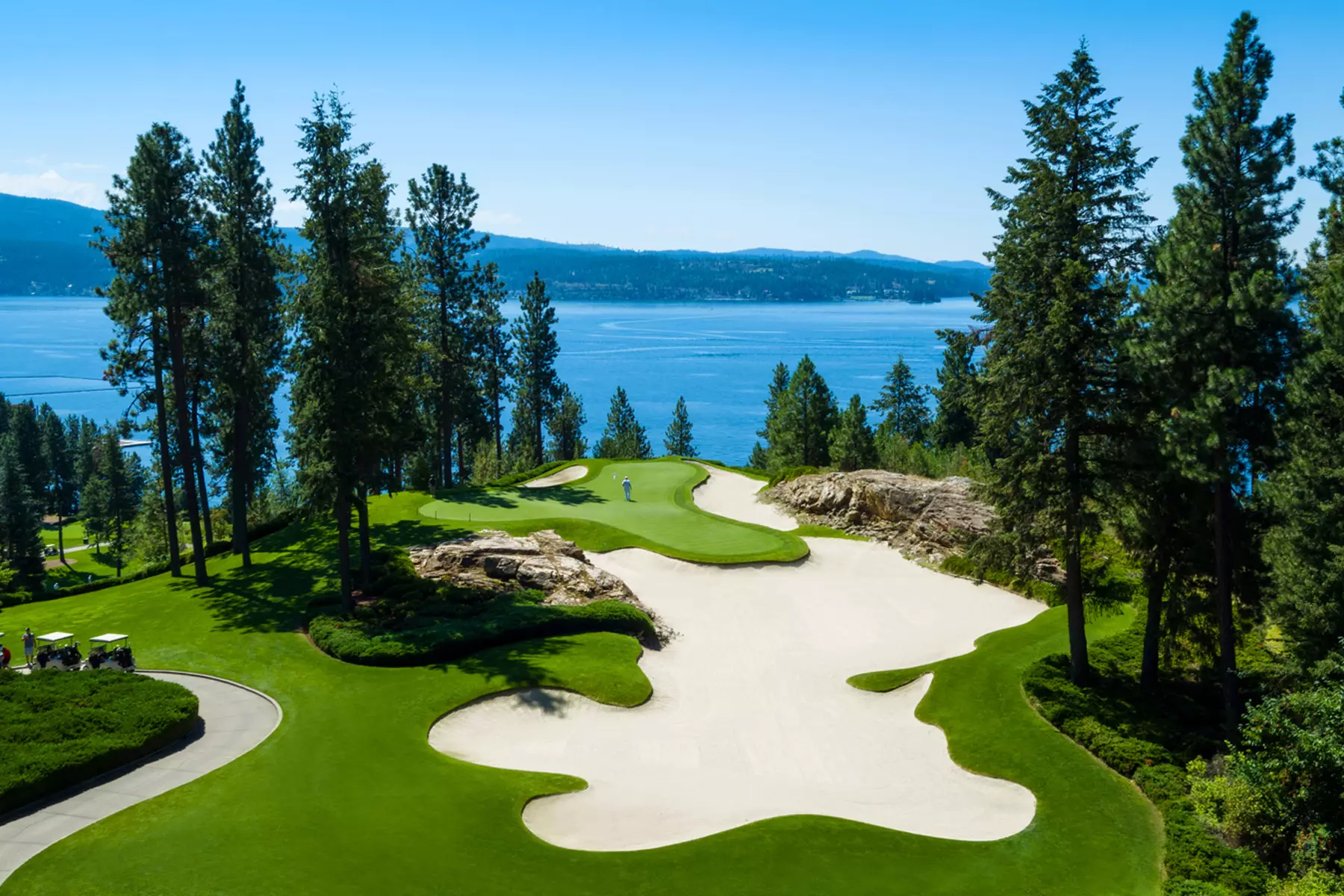 Lapangan golf ing pinggir banyu kanthi pinus dhuwur ing The Coeur d'Alene Resort, Idaho