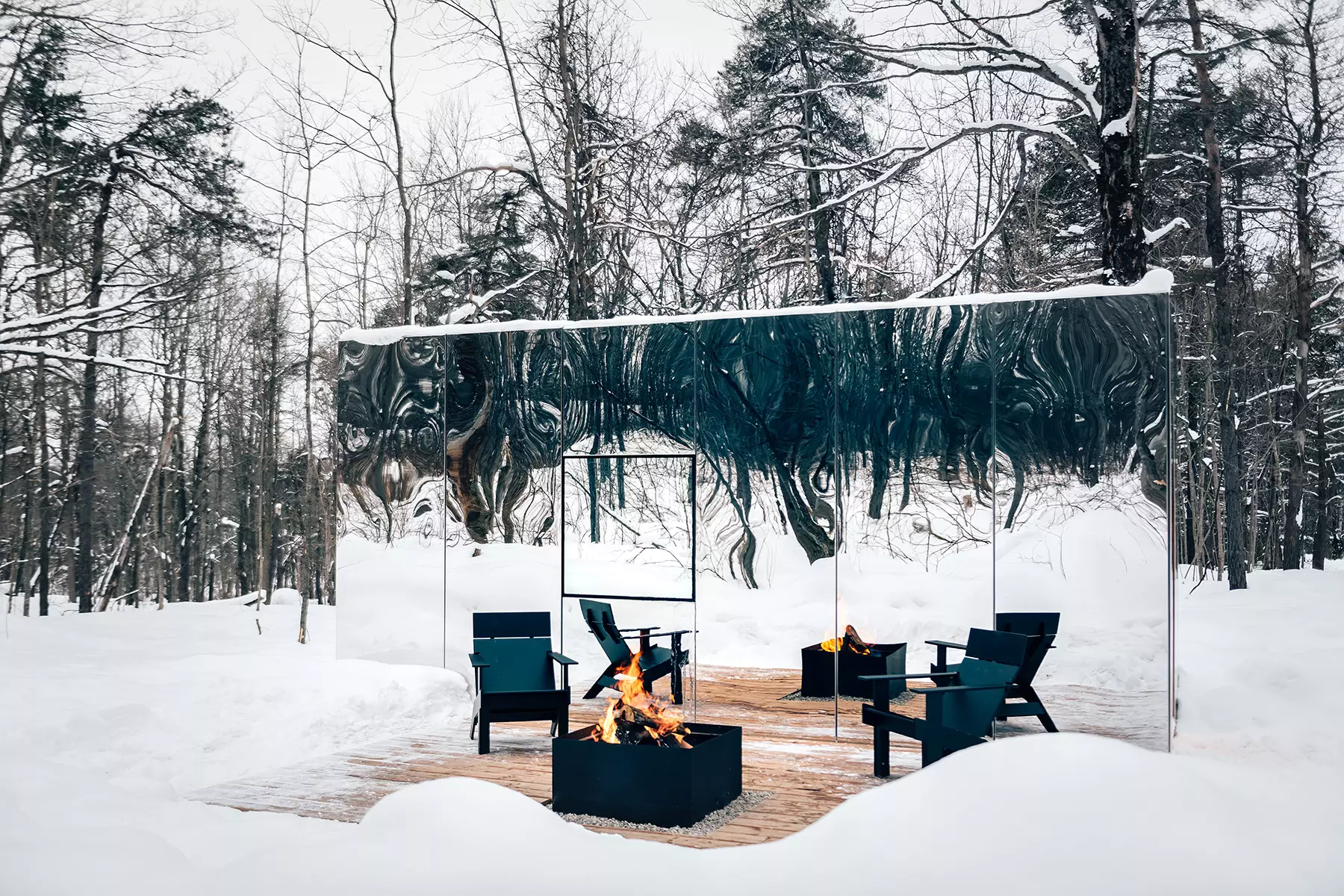 Stoličky okolo ohniska v zrkadlovej chatke v Kanade počas zimy