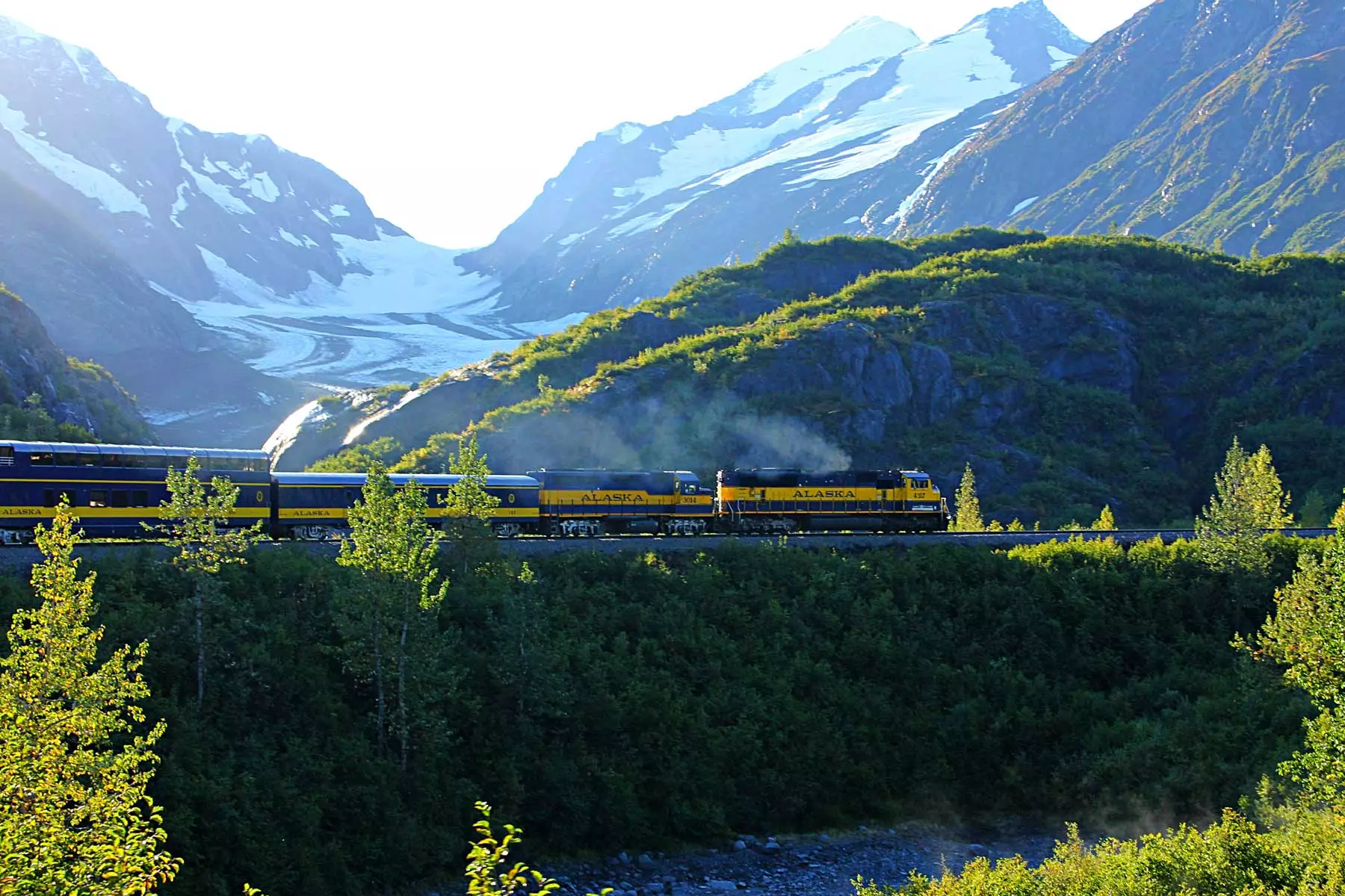 ລົດໄຟ Alaska Railroad ແລ່ນຜ່ານສະພາບແວດລ້ອມສີຂຽວໃກ້ກັບ Bartlett Glacier