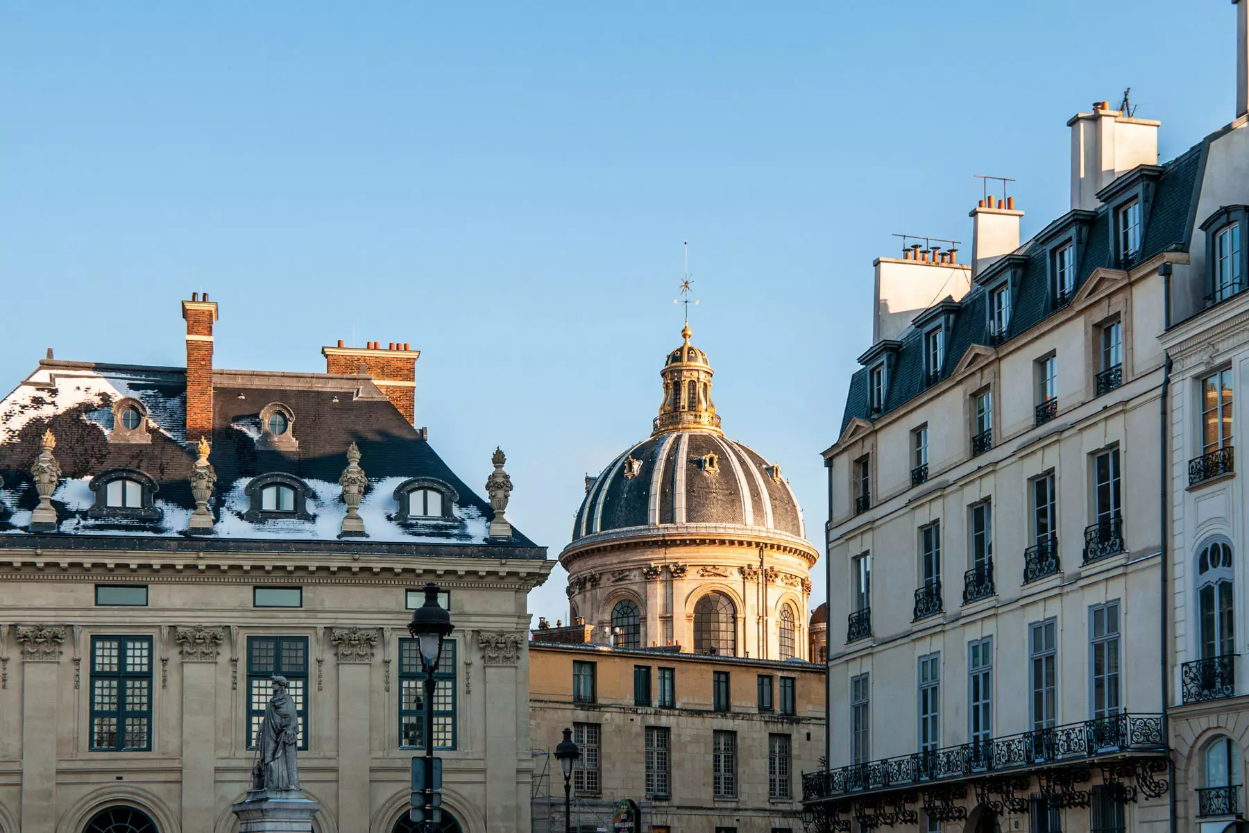 Edifícios em Paris durante o inverno com um pouco de neve e luz solar dourada