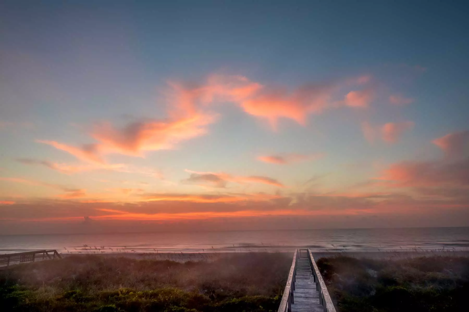 I-Sunset Sky-Clouds njengengemuva, nesihlabathi solwandle nokuhamba ngezinyawo kwebhodi e-Amelia Island eFlorida