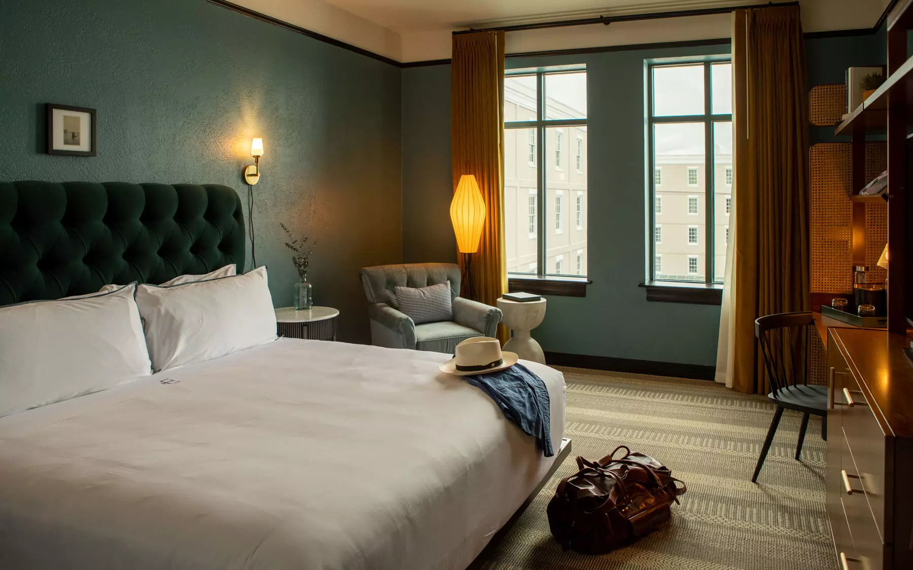 Kamar hotel besar dengan tempat tidur, topi, dan tas ransel kulit