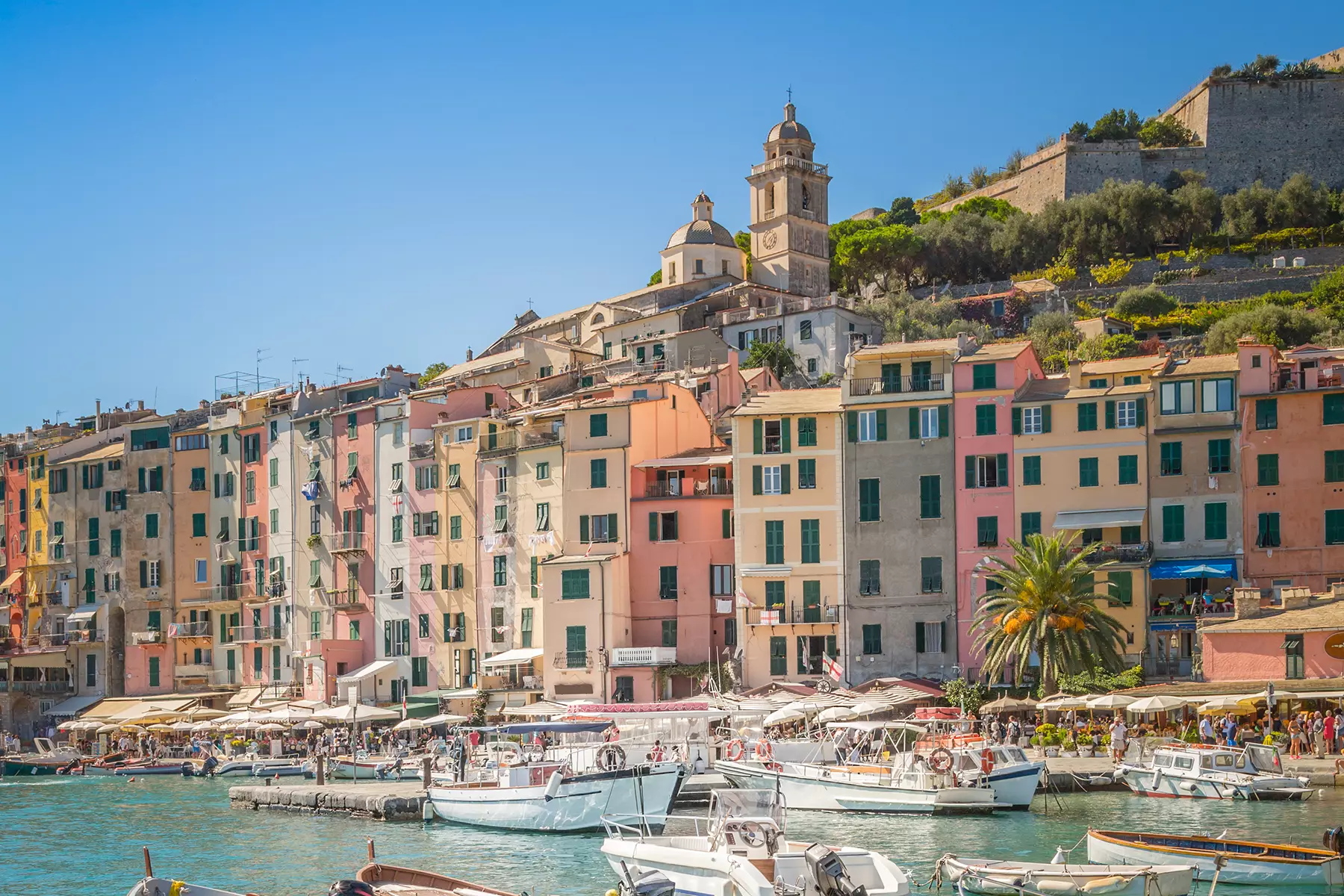 Portovenere၊ Liguria၊ အီတလီနိုင်ငံရှိ ဆိပ်ကမ်း San Lorenzo Romanesque ဘုရားကျောင်းမှ လှေငယ်များနှင့် ရောင်စုံအိမ်များ။