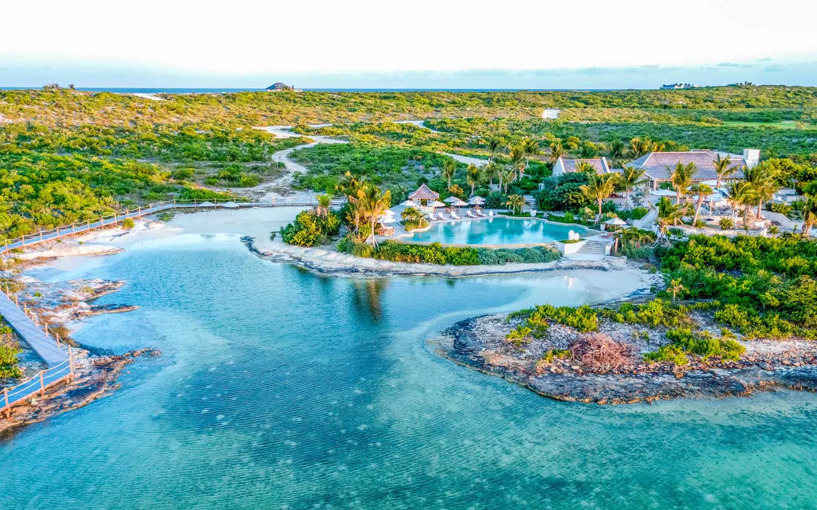 Veduta mill-ajru tar-resort ta' Ambergris Cay fit-Turks u Caicos, b'ilma turkważ u pajsaġġ aħdar lush