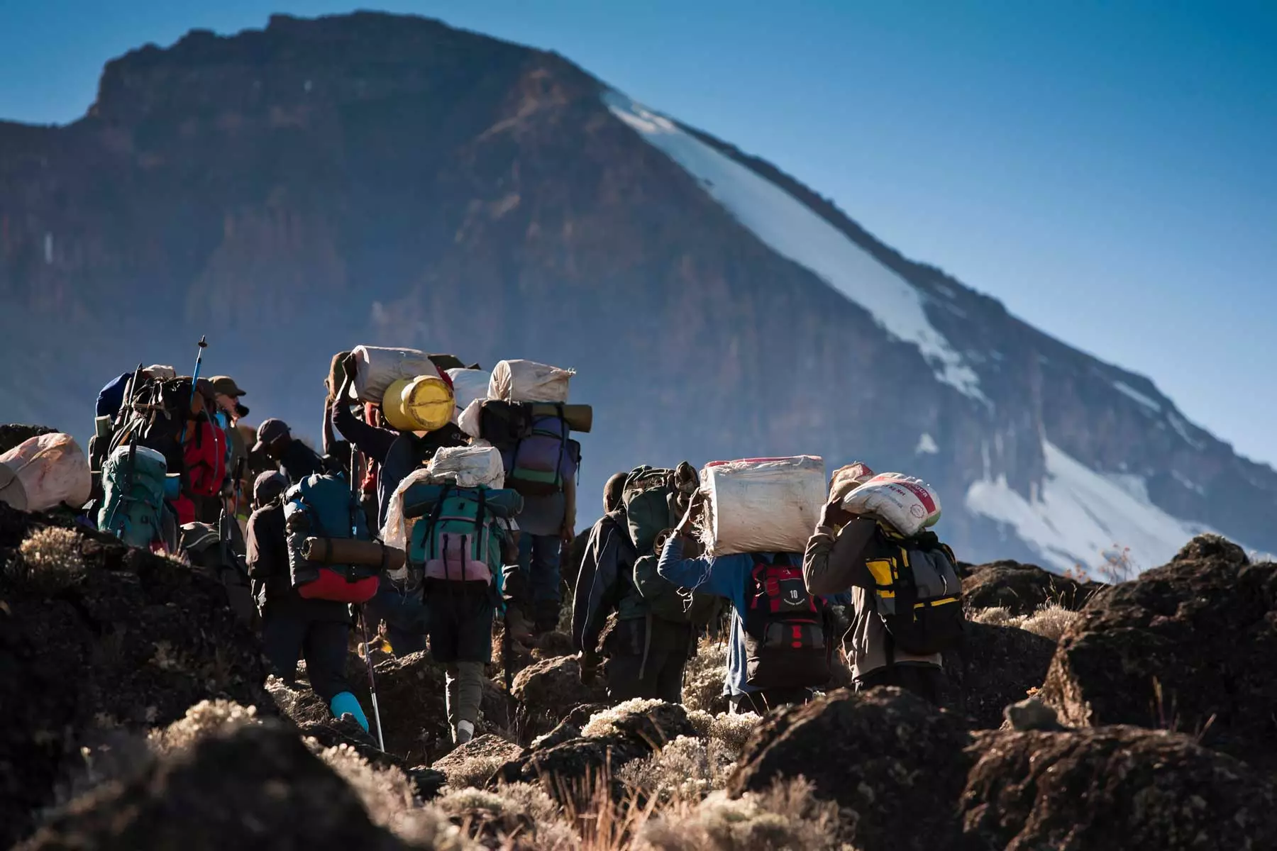 Kilimanjaro tog'idagi Lemosho yo'lidagi Shira 2-lageri ustidagi sayyohlar va yukchilar.
