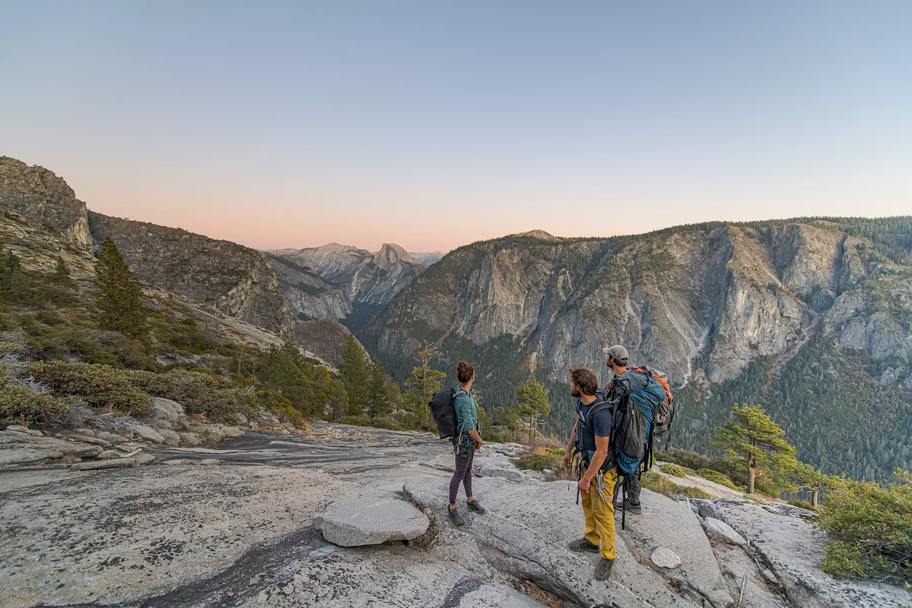 Masu tafiya uku suna kallon Half Dome daga El Capitan faɗuwar rana Yosemite