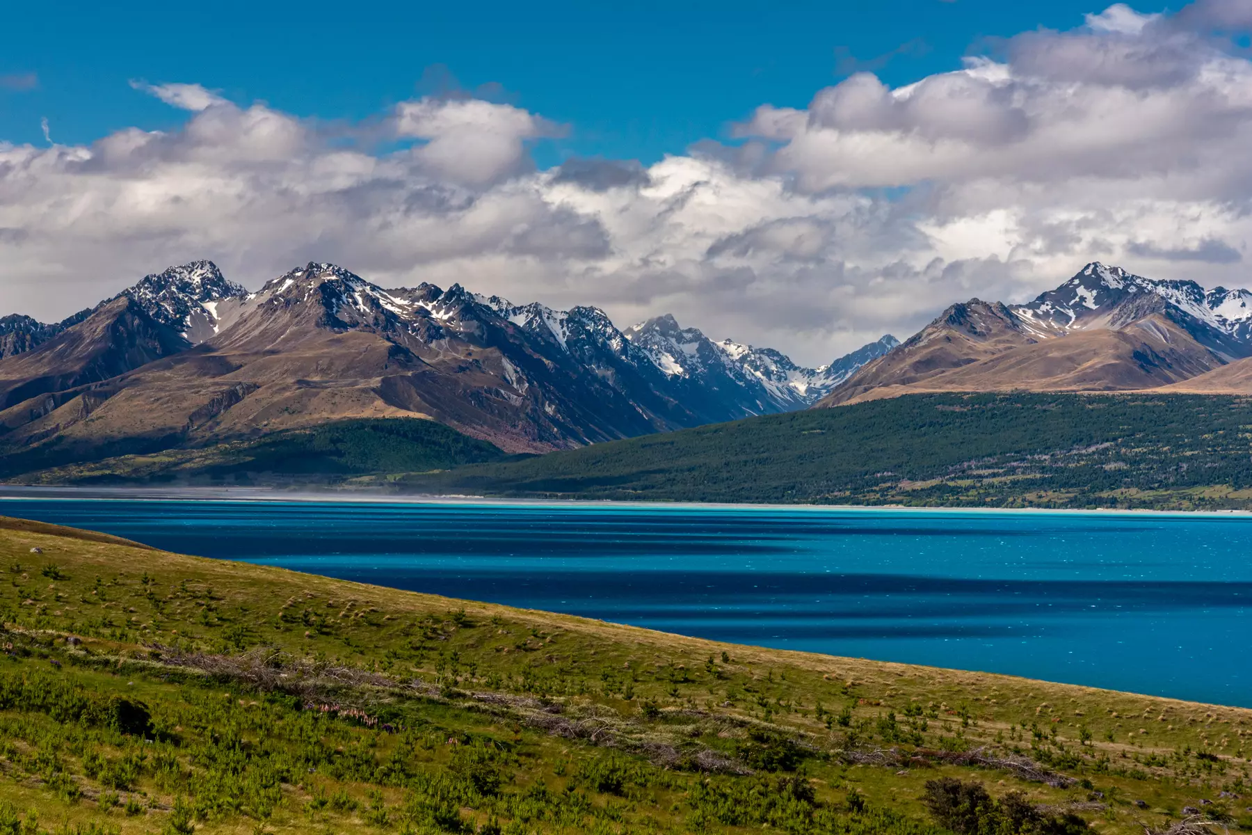 Molnig blå himmel, stor blå vattenmassa och berg i Queenstown, Nya Zeeland