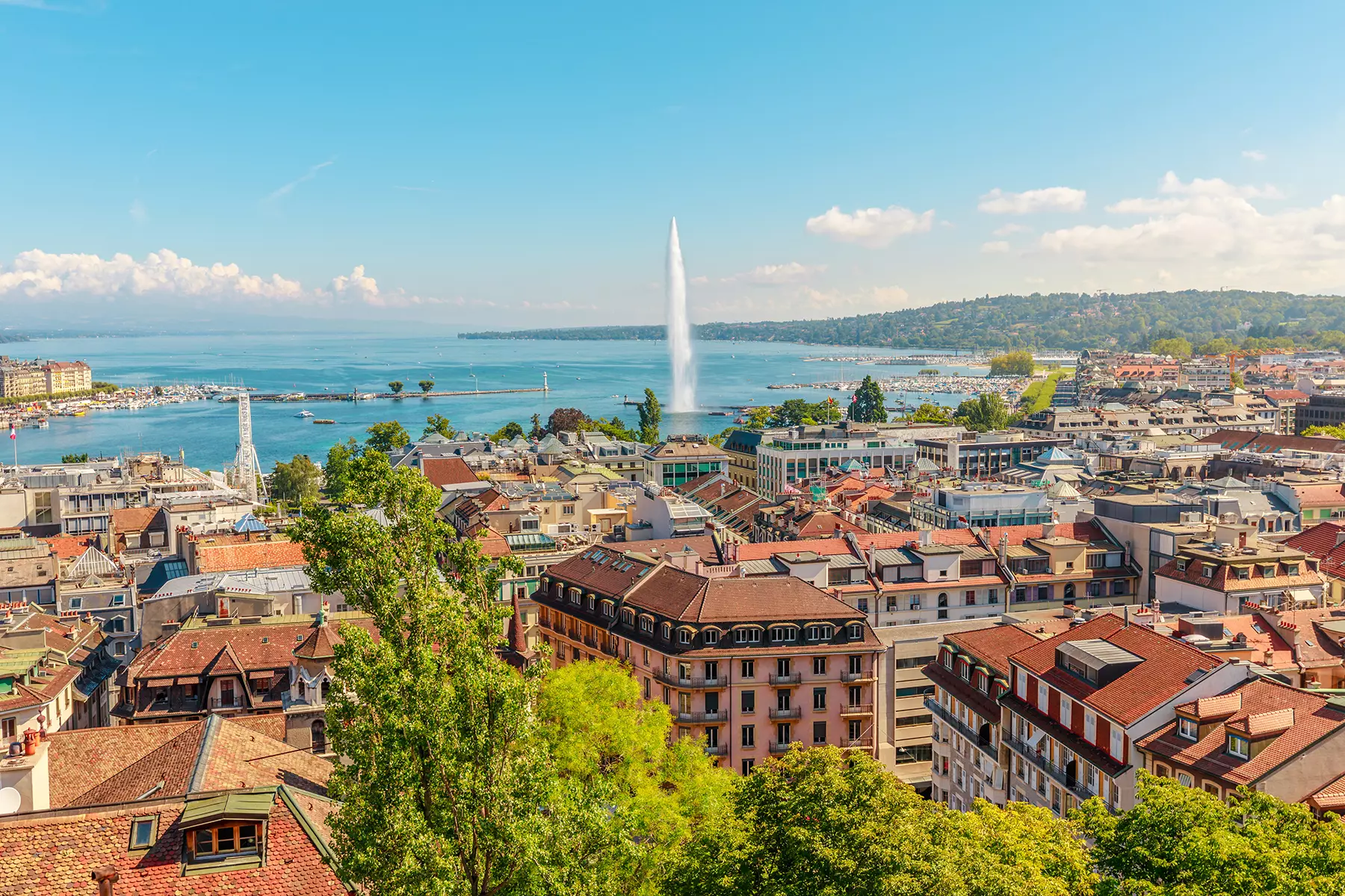 Panoráma mesta Ženeva, francúzsko-švajčiarske vo Švajčiarsku. Letecký pohľad na fontánu Jet d'eau, jazero Leman, záliv a prístav zo zvonice katedrály Saint-Pierre