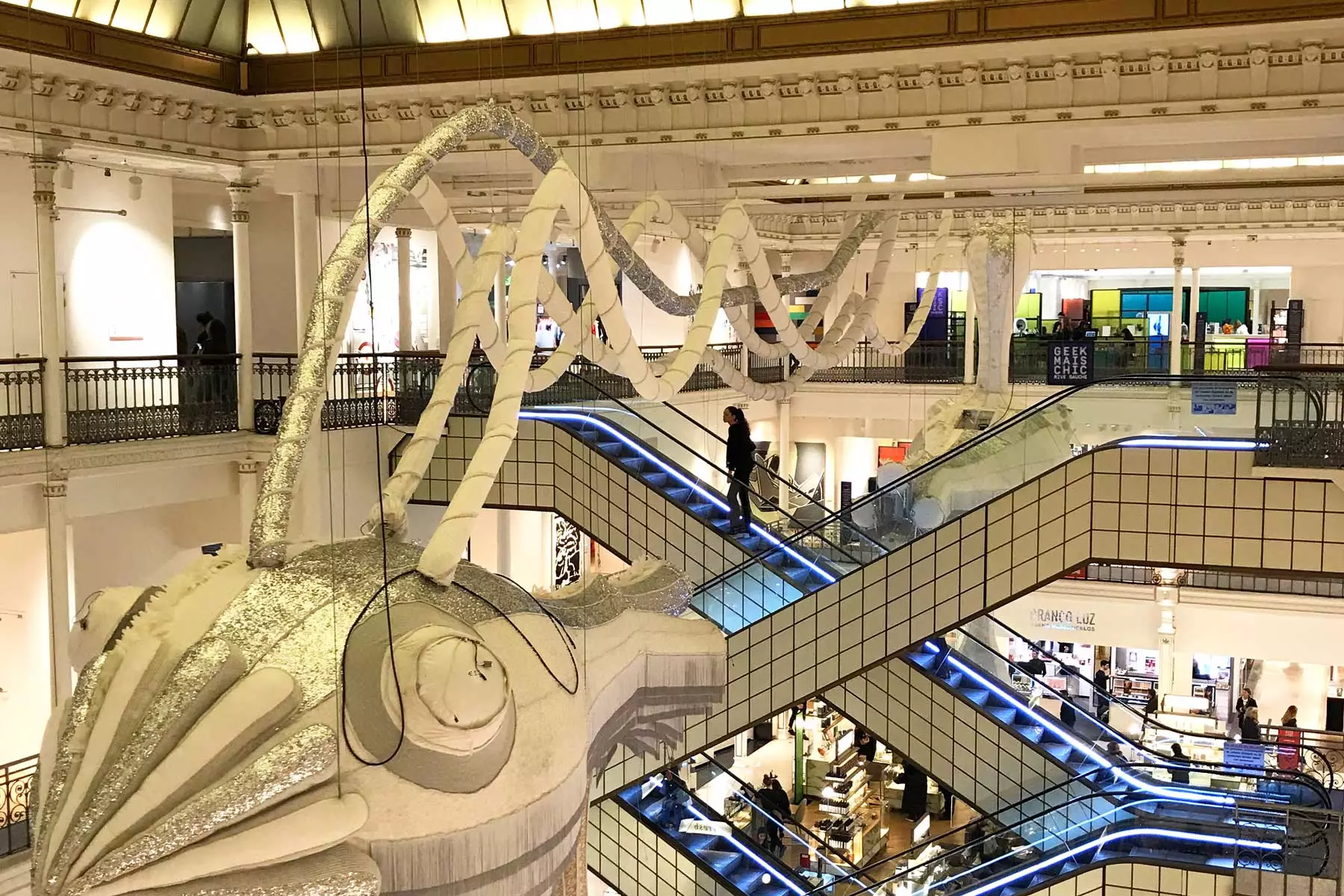 Interior de La Bon Marche en París con escaleras mecánicas icónicas