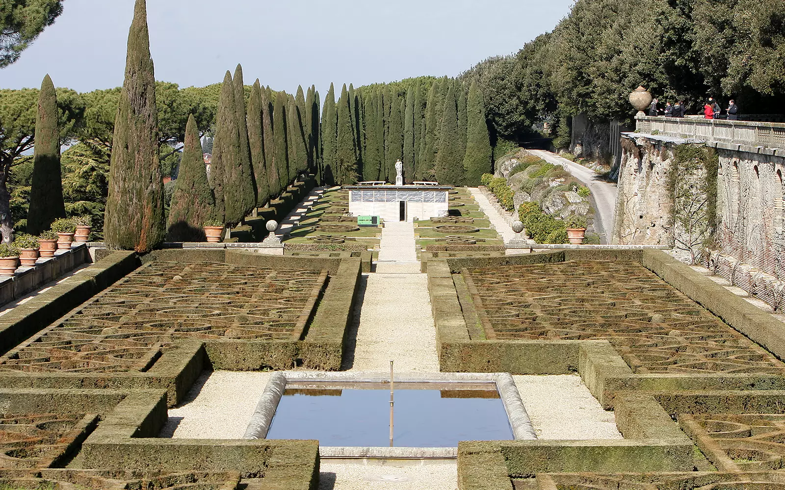 人々は、イタリアのローマにあるカステルガンドルフォのポンティフィカル邸宅の庭園の上に立っています。