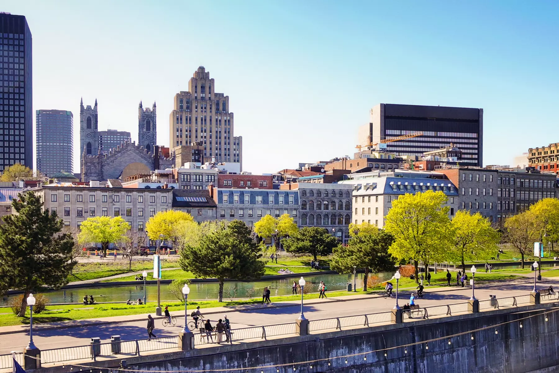 Vieux port de Montreal dhe horizonti në qendër të qytetit me skelë shëtitore në një ditë të pastër pranvere maji me njerëz që ecin në distancë