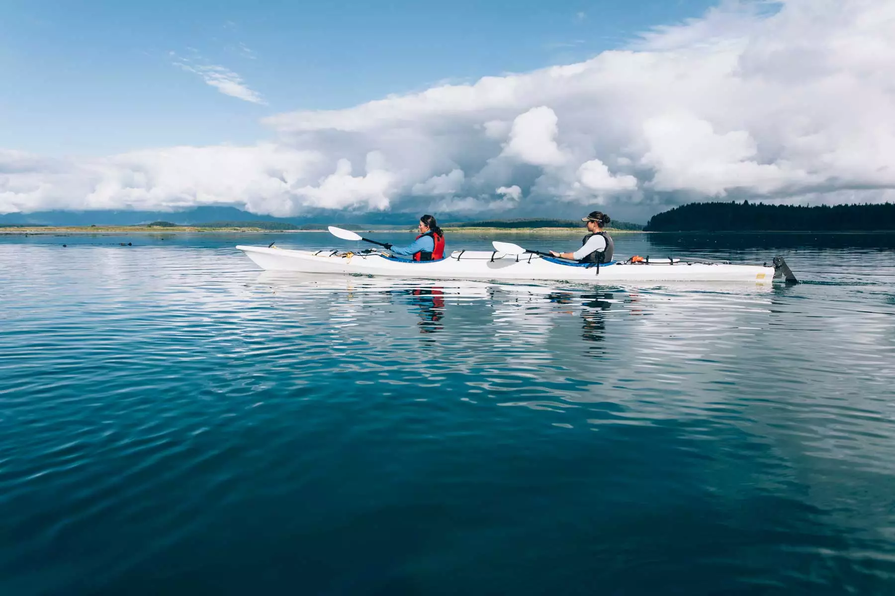 Kayakers-badeedka oo ku boodboodaya biyaha nadiifka ah ee meel laga soo galo ee xeebta Alaska.