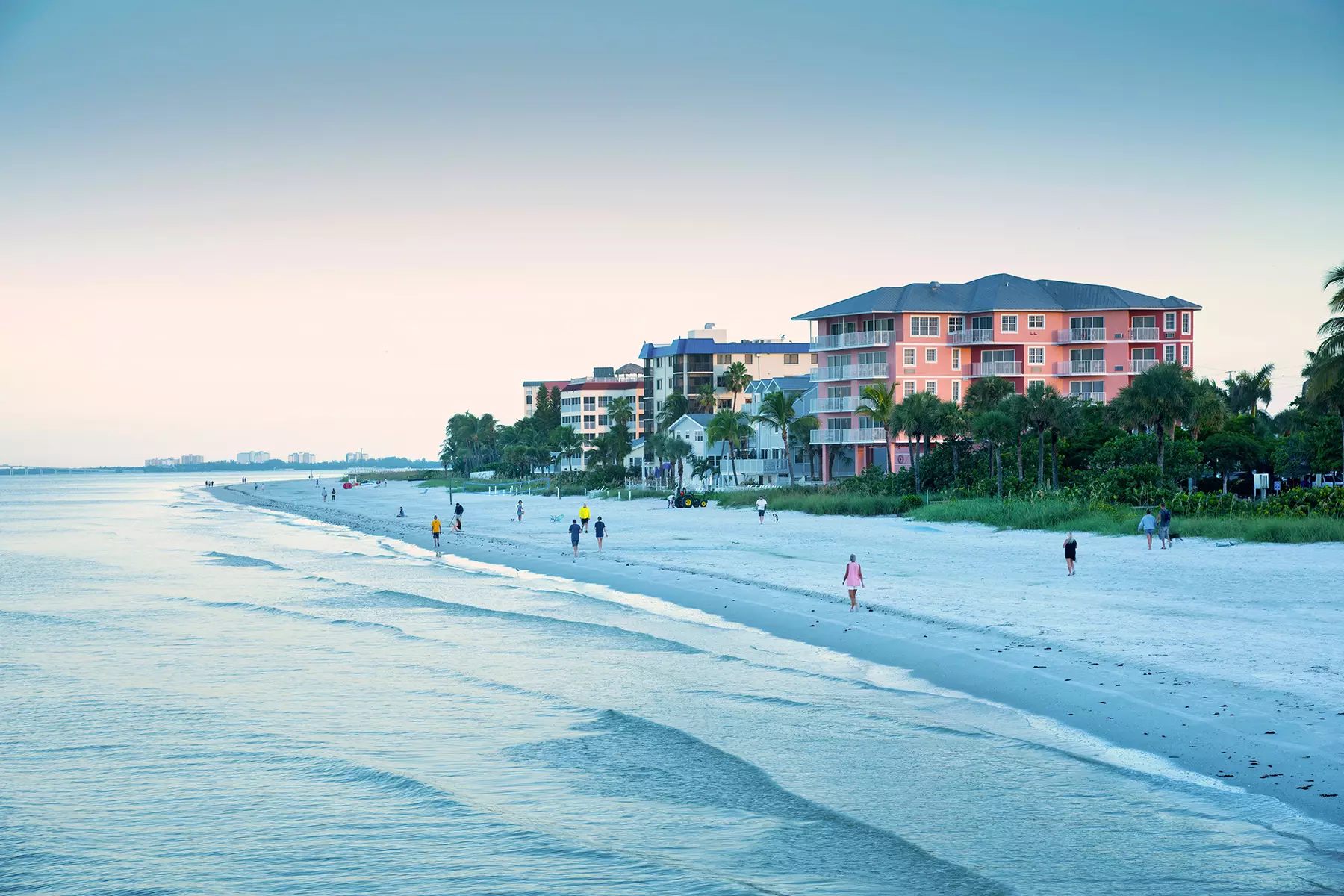 Wschód słońca przenosi spacerowiczów po plaży na plażę Fort Myers znajdującą się na wyspie Estero nad Zatoką Meksykańską.