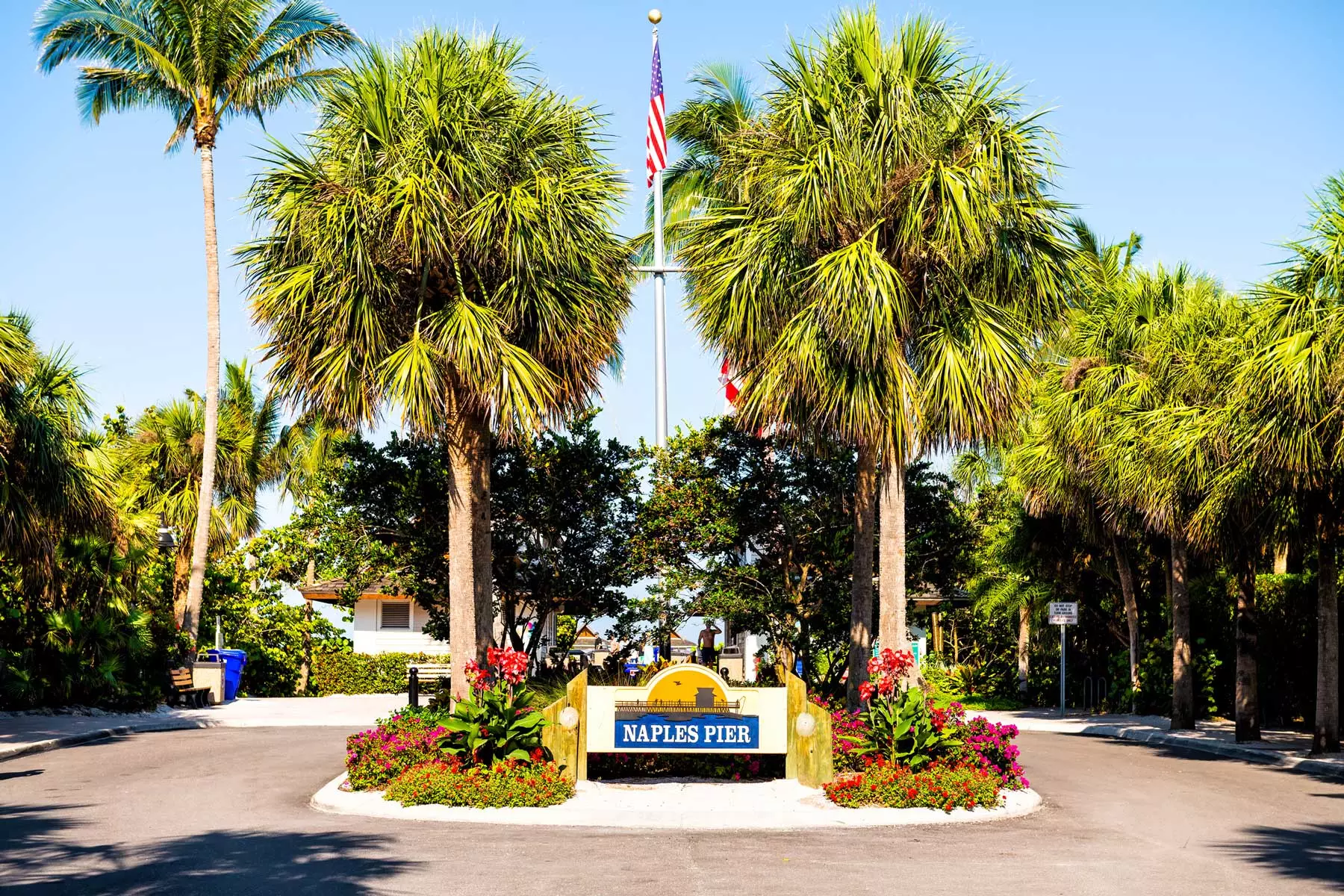 Cartell d'entrada del moll de Naples, Florida amb palmeres i bandera americana al pal de la bandera a una comunitat de barri ric