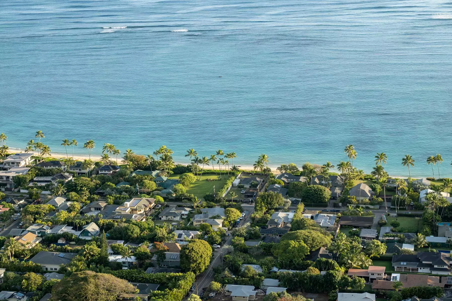 Kutuluka kwa dzuwa kumawunikira nyumba zapamwamba za m'dera la Lanikai. Awa ndi mawonedwe ochokera ku Lanikai Pillbox trail.