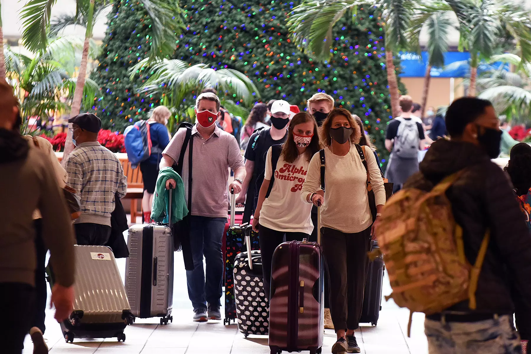 Reizigers met gezichtsmaskers komen de dag voor Kerstmis aan op Orlando International Airport