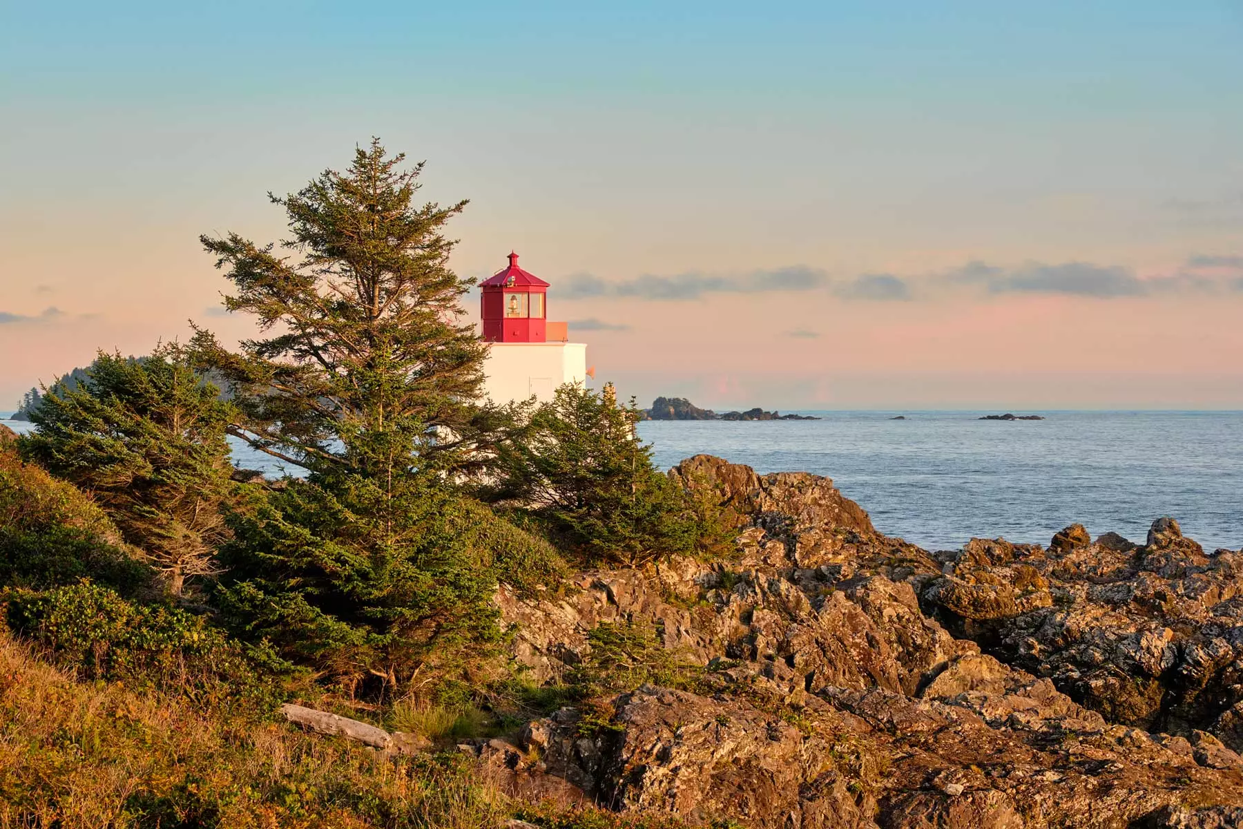 Ilunabarrean, Ucluelet-eko Wild Pacific Trailaren ondoan dagoen itsasargia Ozeano Barera begira dagoen itsasertz malkartsu batean dago.