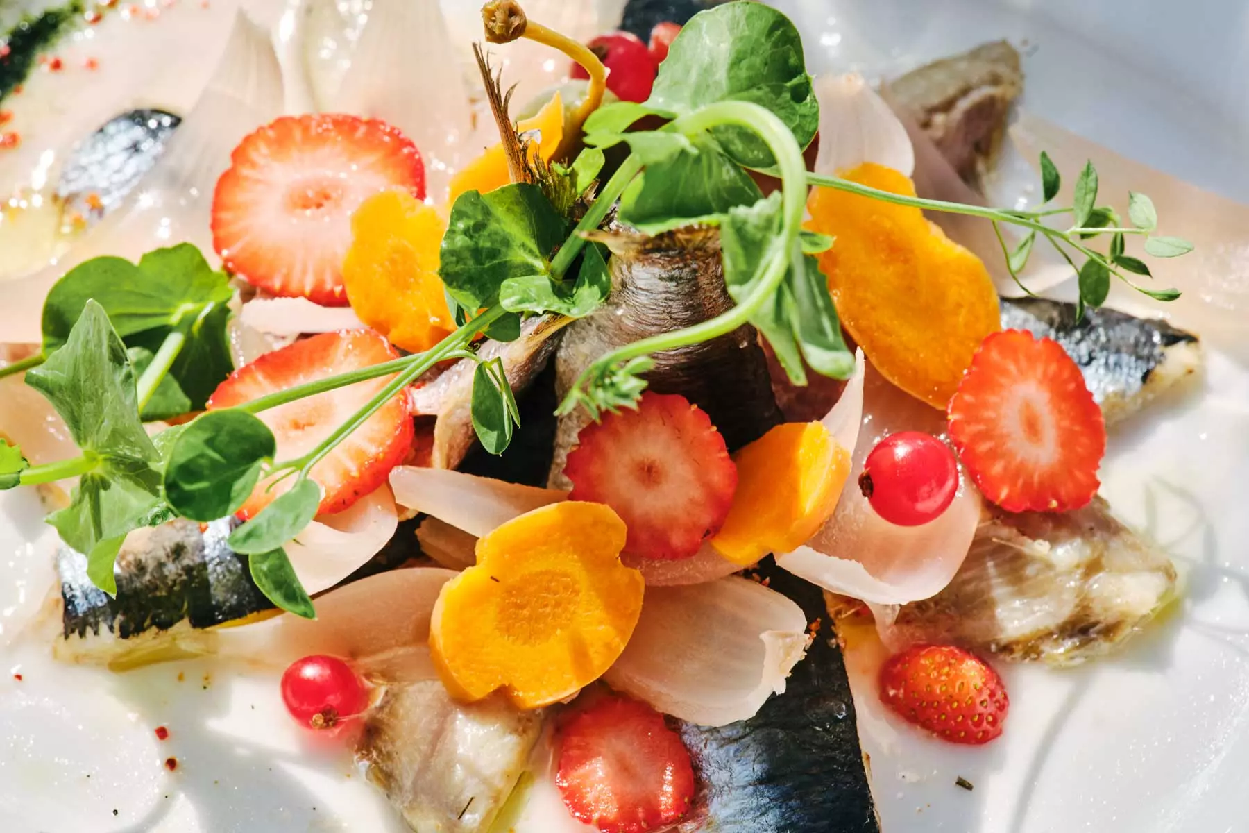 La photo en gros plan d'un plat apéritif avec fraises, carottes, sardines et légumes verts dans un restaurant de l'Ile de Ré, France