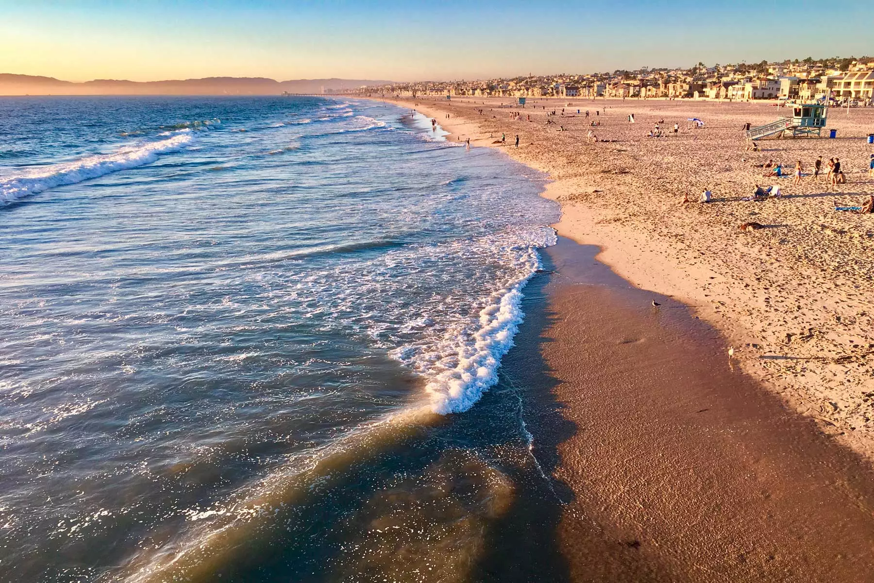 Hermosa Beach, Kalifornia partvonala hullámokkal és otthonokkal a távolban