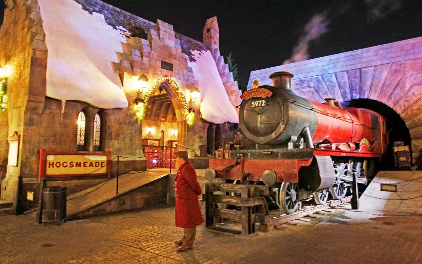 O locomotivă aburindă la Hogsmeade în timpul unui eveniment de previzualizare nocturnă de Crăciun în Wizarding World of Harry Potter