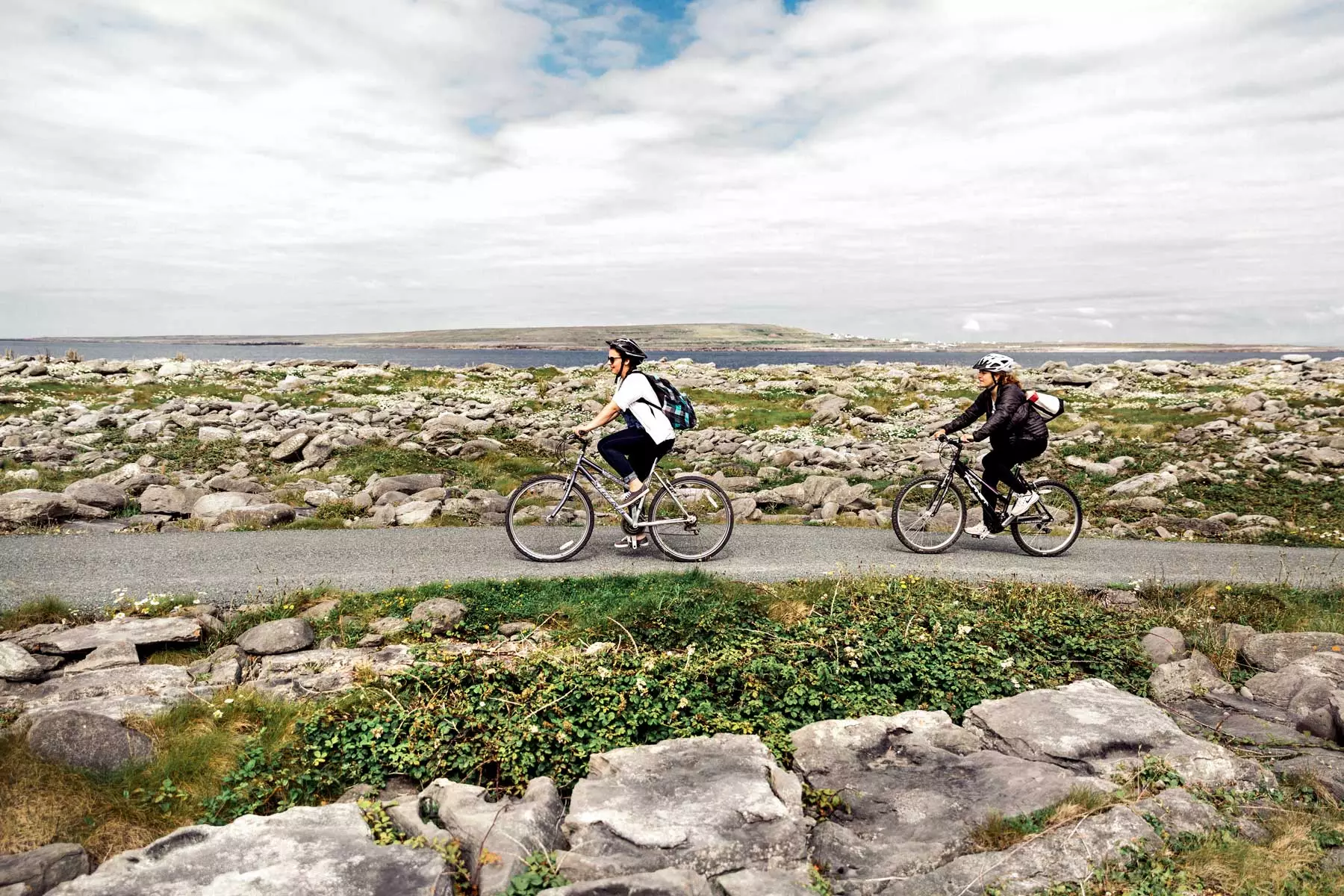 Dua cyclists Ngalanglang bentang windswept of Inis Oírr di Irlandia