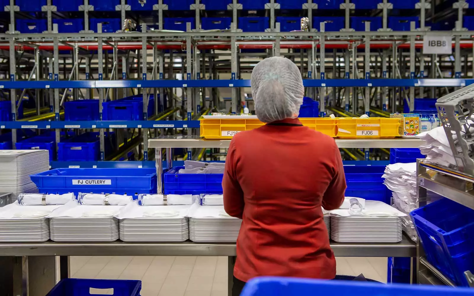 Bulkartikelen worden geladen terwijl trays worden opgesteld voordat de bemanning aan boord van het vliegtuig gaat.