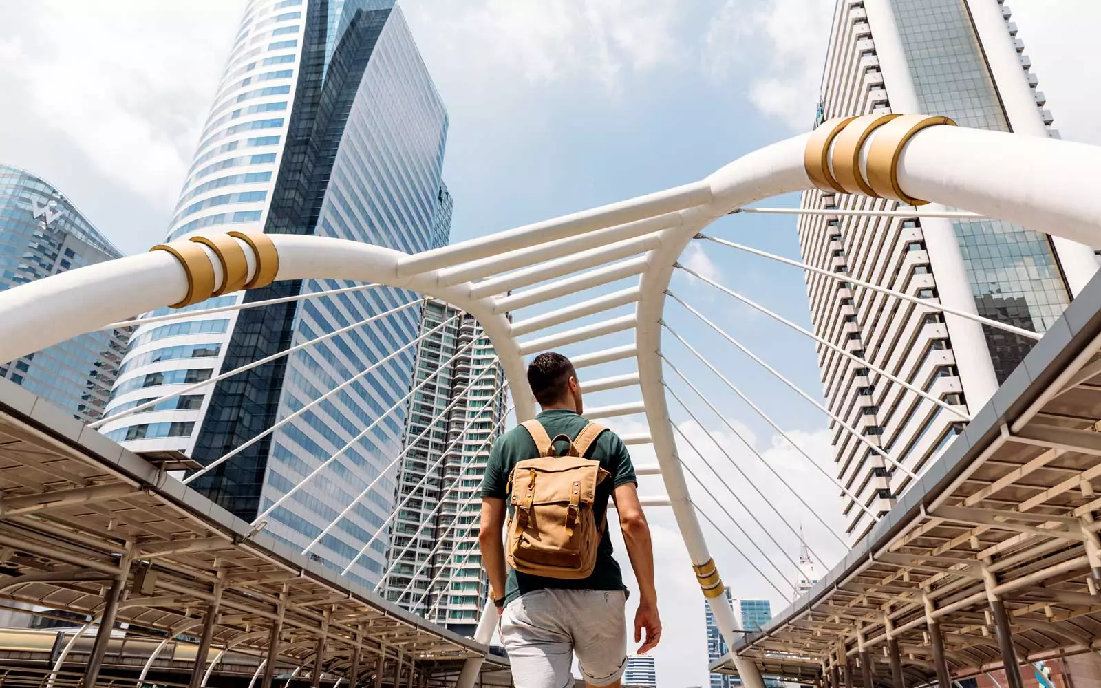 Vista traseira de um homem com mochila admirando modernos arranha-céus em Bangkok, Tailândia