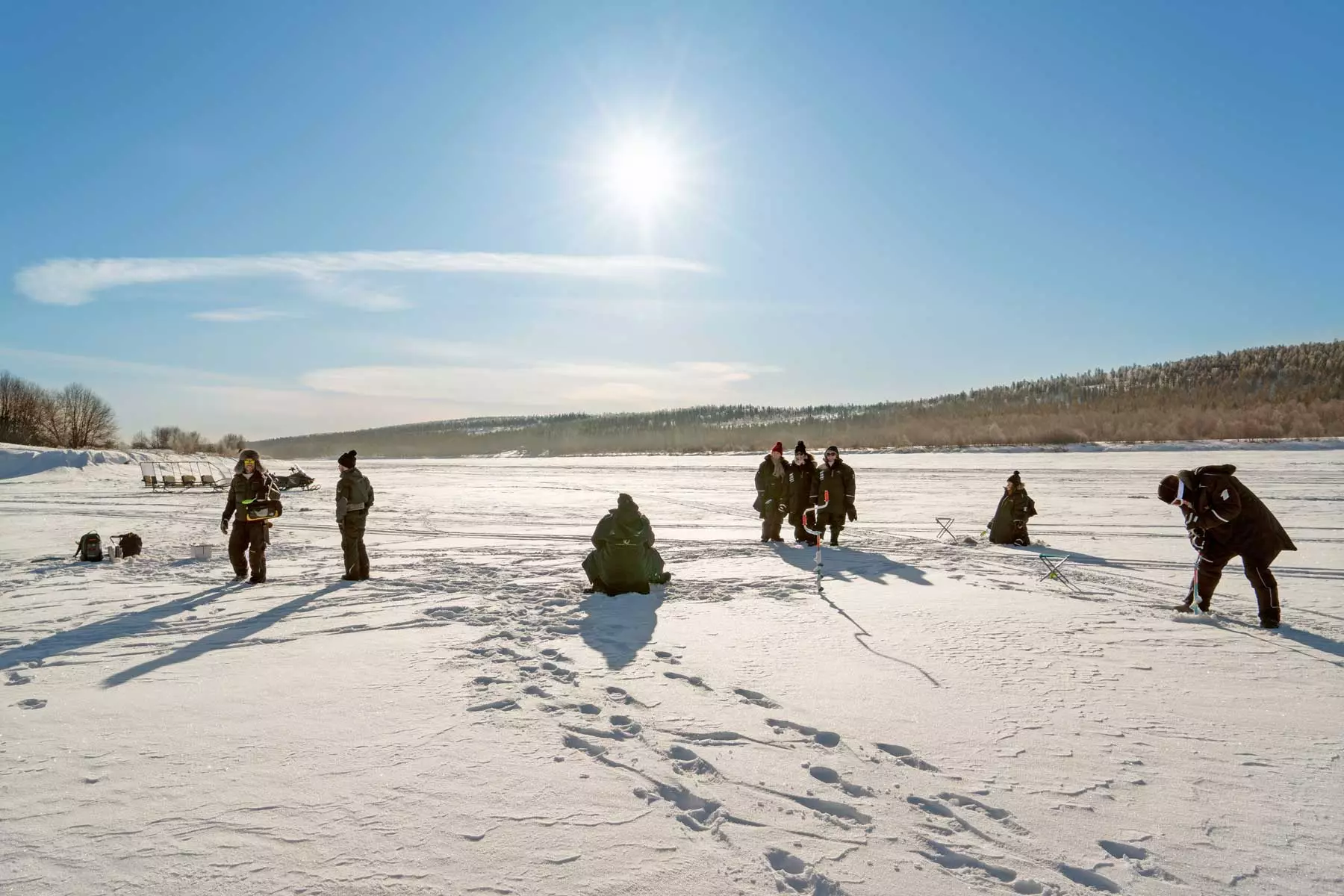 Een groep mensen is verspreid over een bevroren meer in Finland en leert ijsvissen