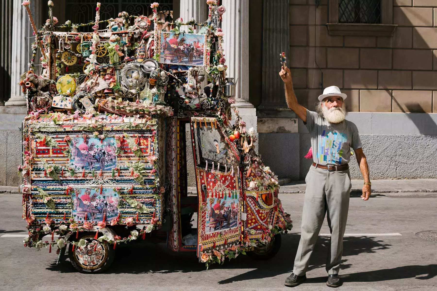 Mężczyzna przed samochodem udekorowanym na cześć Santa Rosalia na ulicach Palermo
