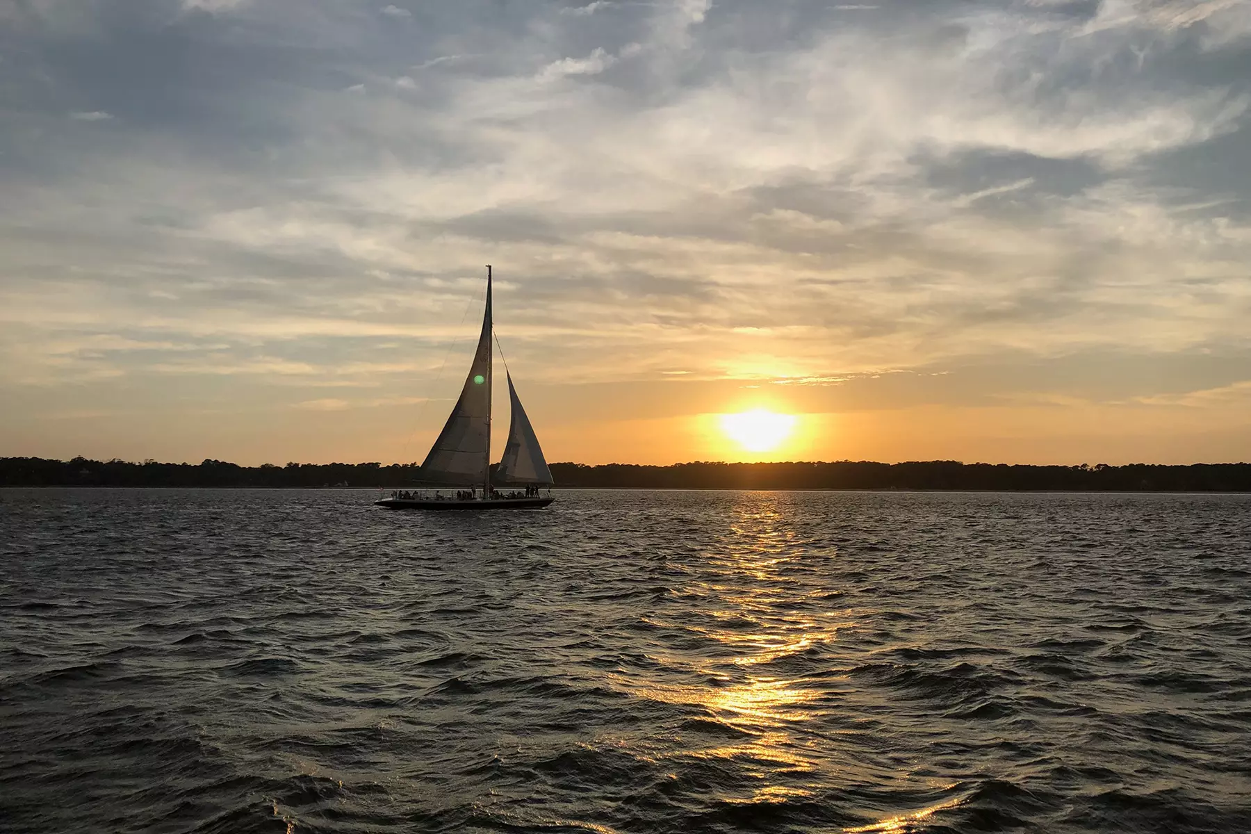 Um veleiro Vagabond Cruise na água durante o pôr do sol