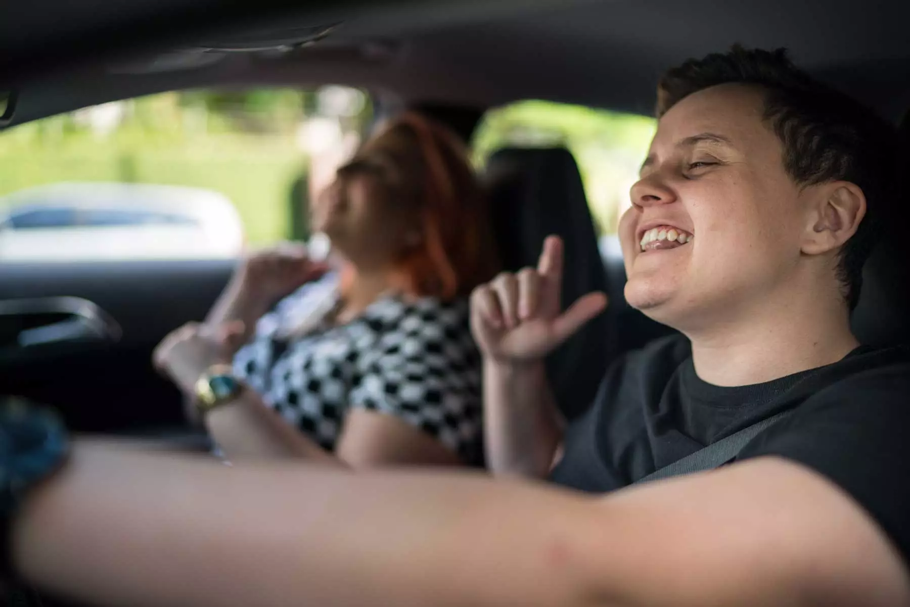 Couple LGBTQ écoutant, chantant, dansant dans la voiture