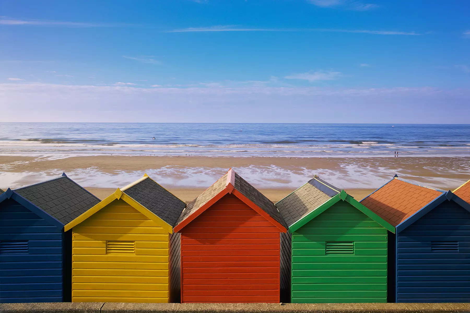 Capanne sulla spiaggia dipinte in una linea, Whitby, Inghilterra, Regno Unito